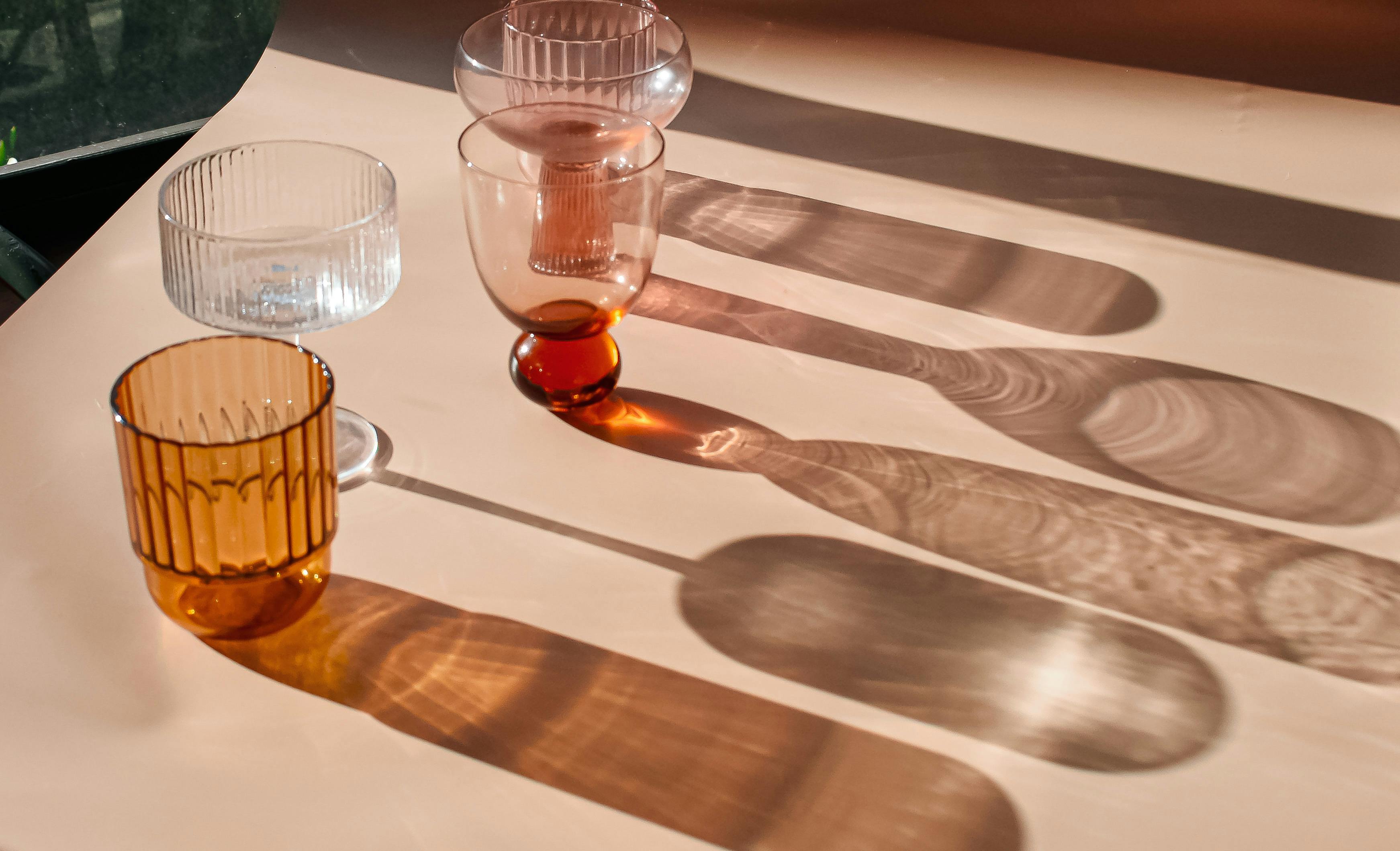 Variety of Glasses Casting Shadows on a Table · Free Stock Photo