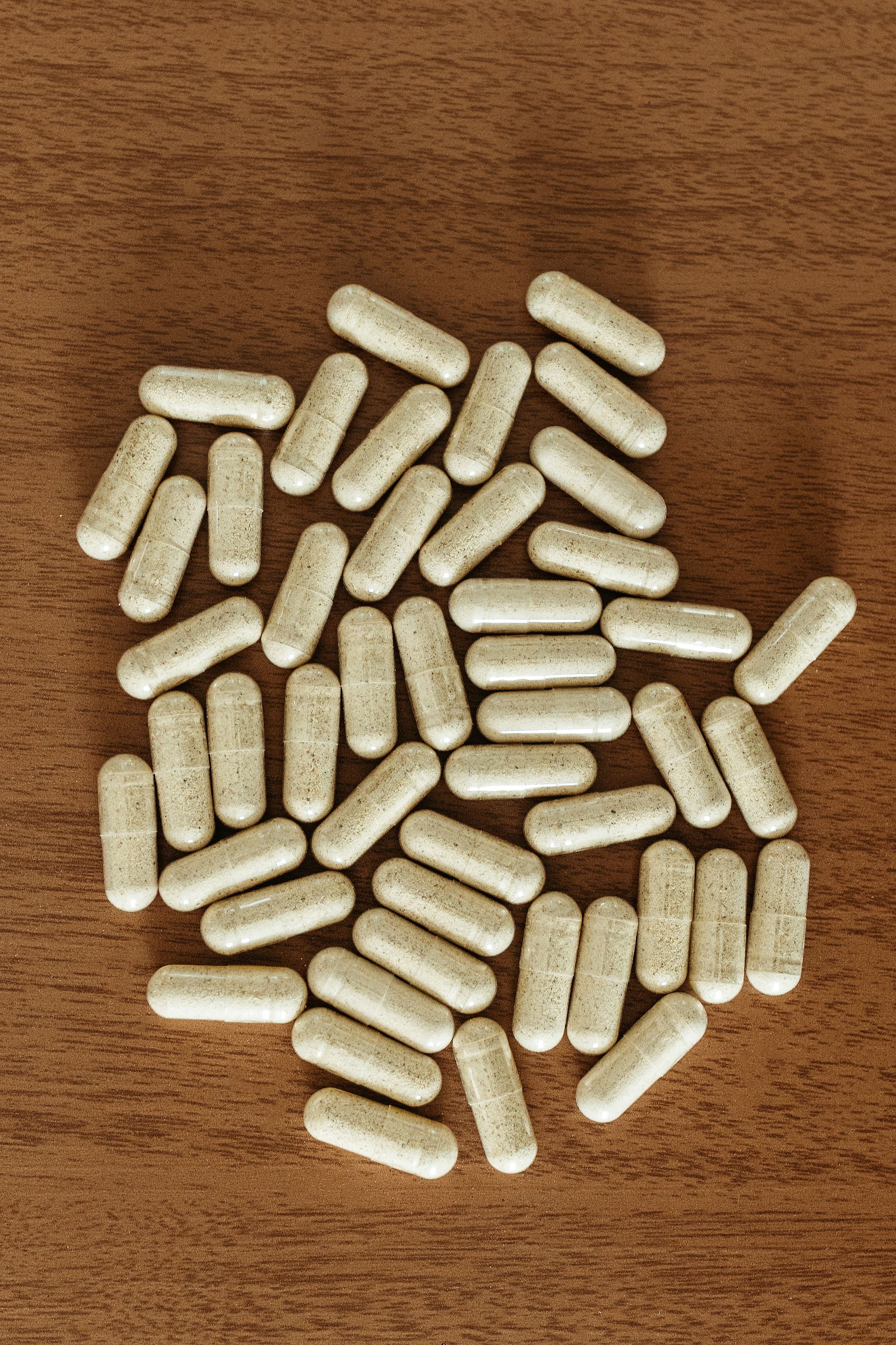 White Capsules Lying on Wooden Table · Free Stock Photo