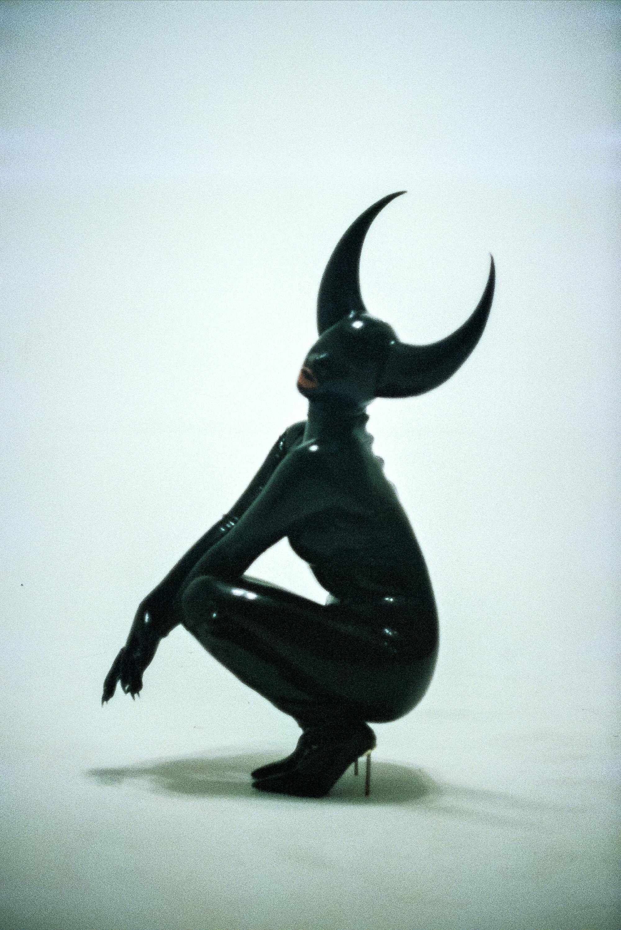Woman in a Black Devil Costume Sitting on the Ground in the Forest ...