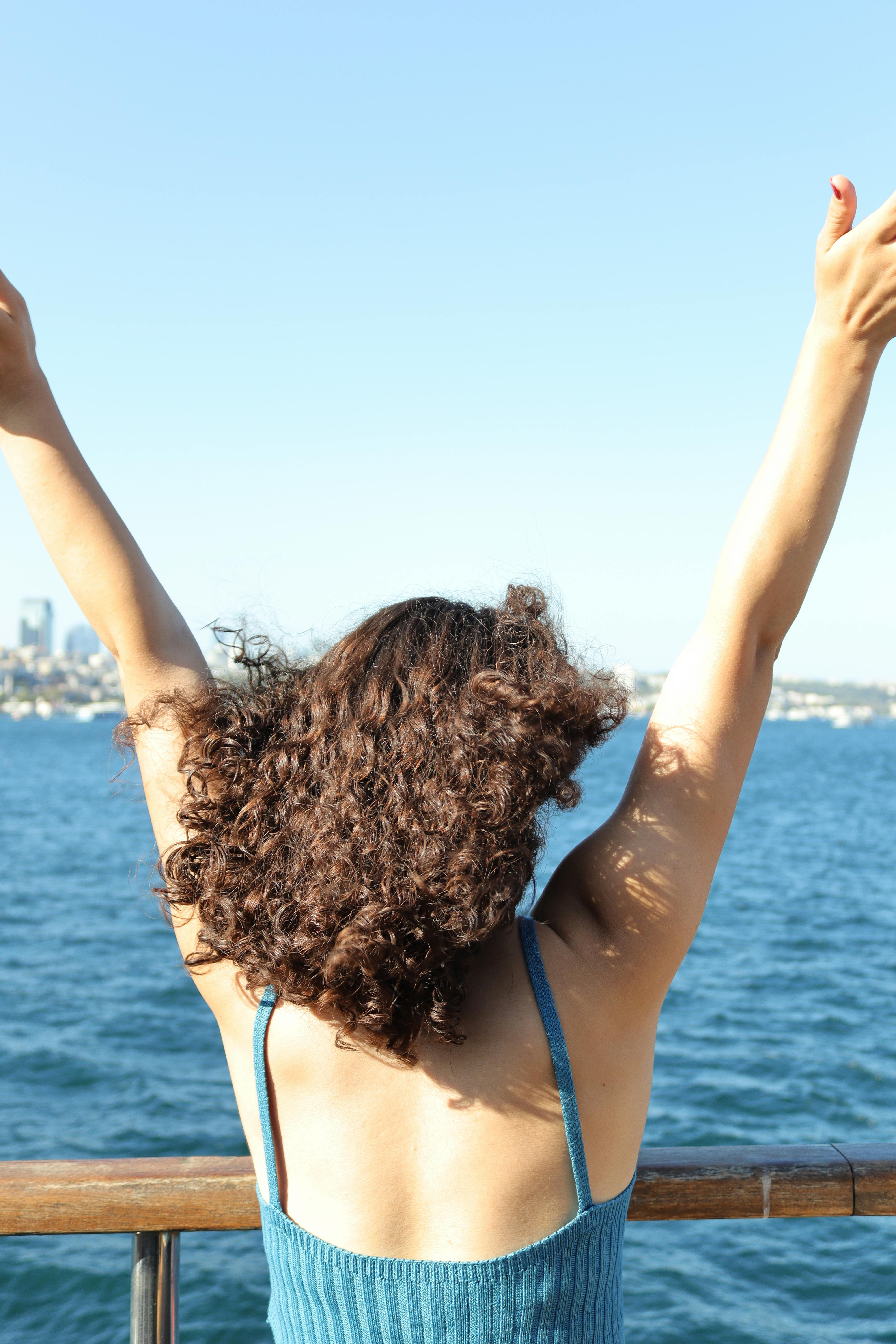 Back View of a Woman Standing on the Pier with Arms Raised · Free Stock ...