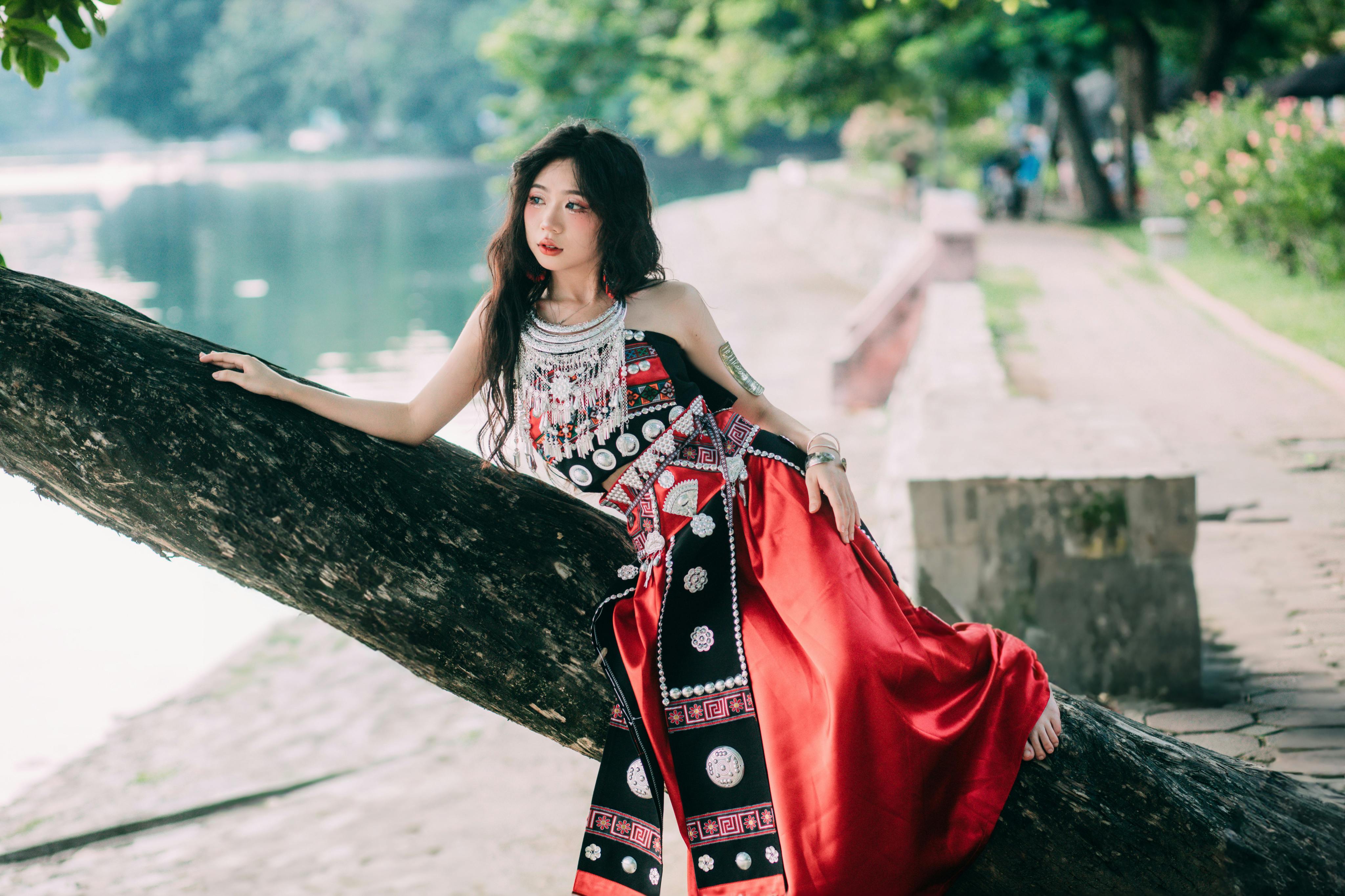 Woman in Traditional Clothing Posing on Bent Tree · Free Stock Photo