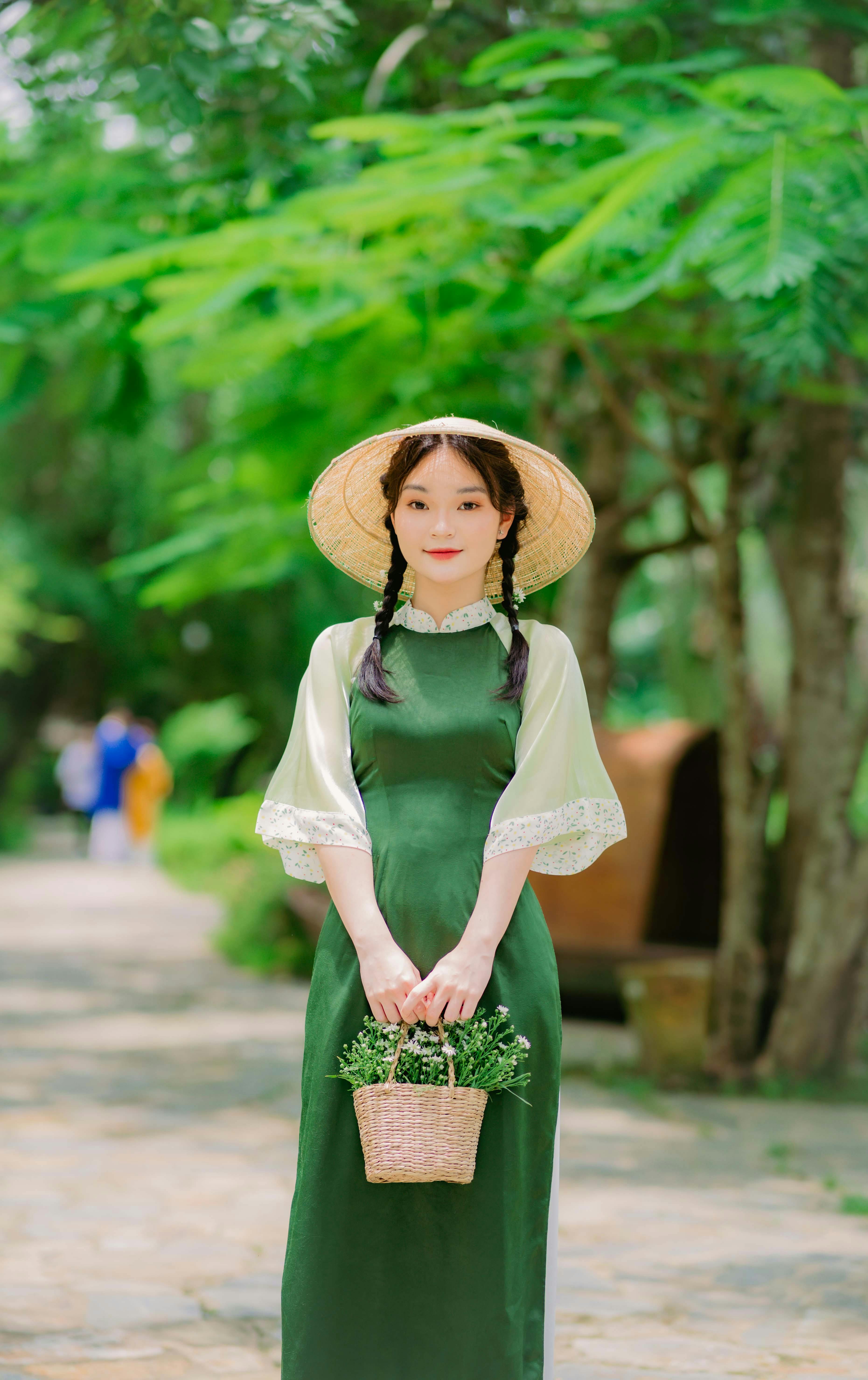 Woman in a Sedge Hat Carrying Flowers · Free Stock Photo