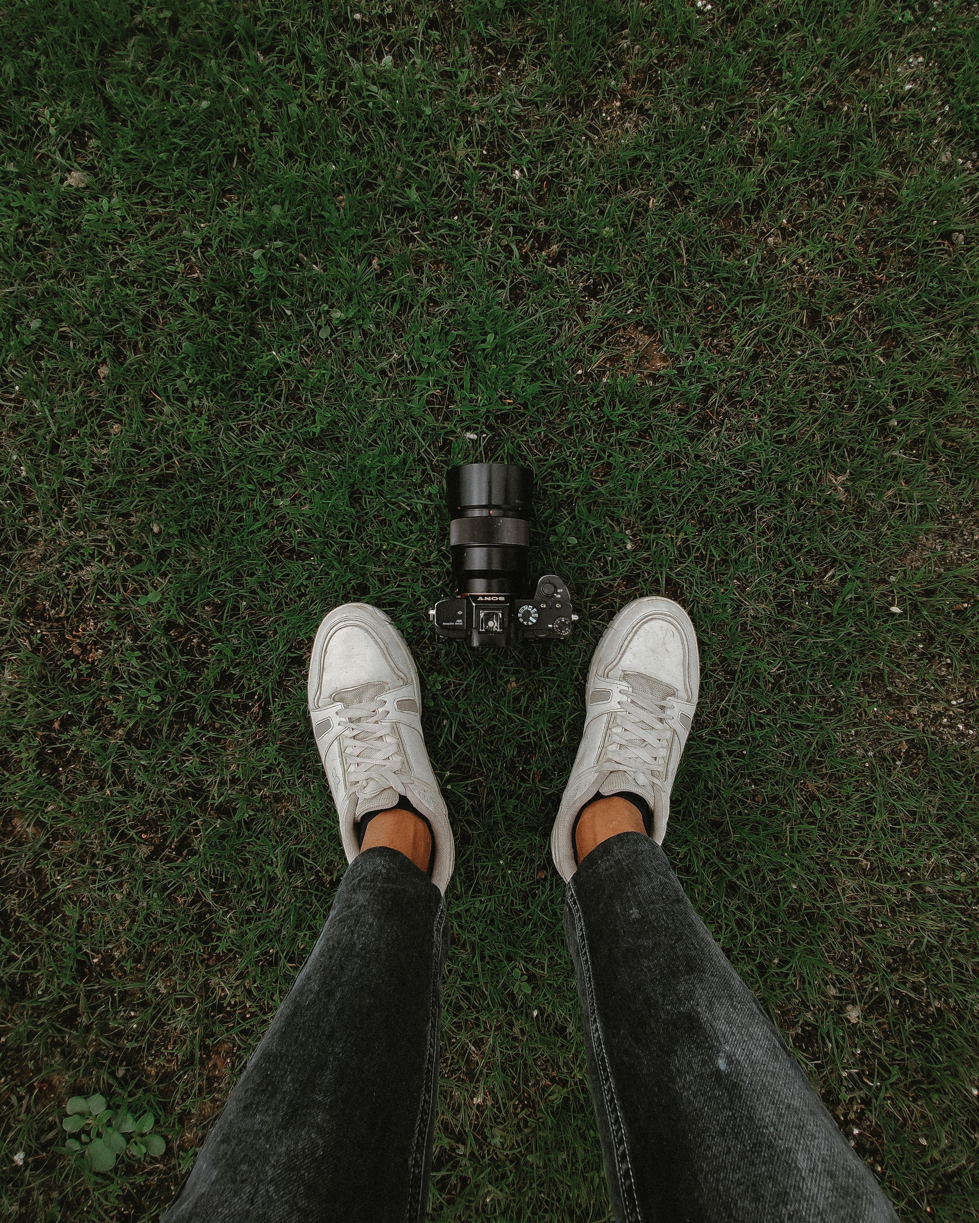 Camera on Grass by Legs of Standing Person · Free Stock Photo