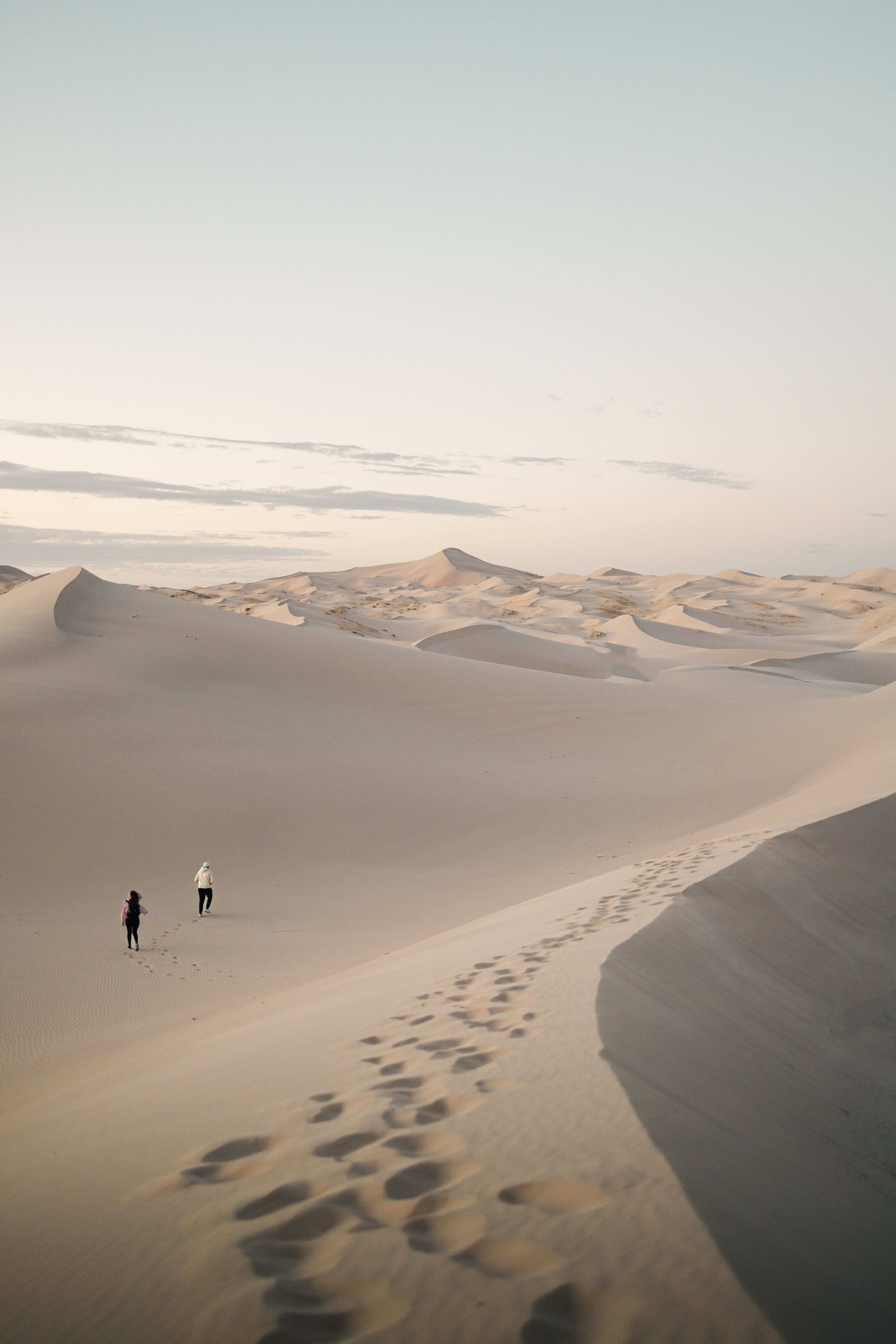 Two people walking through the sand dunes · Free Stock Photo