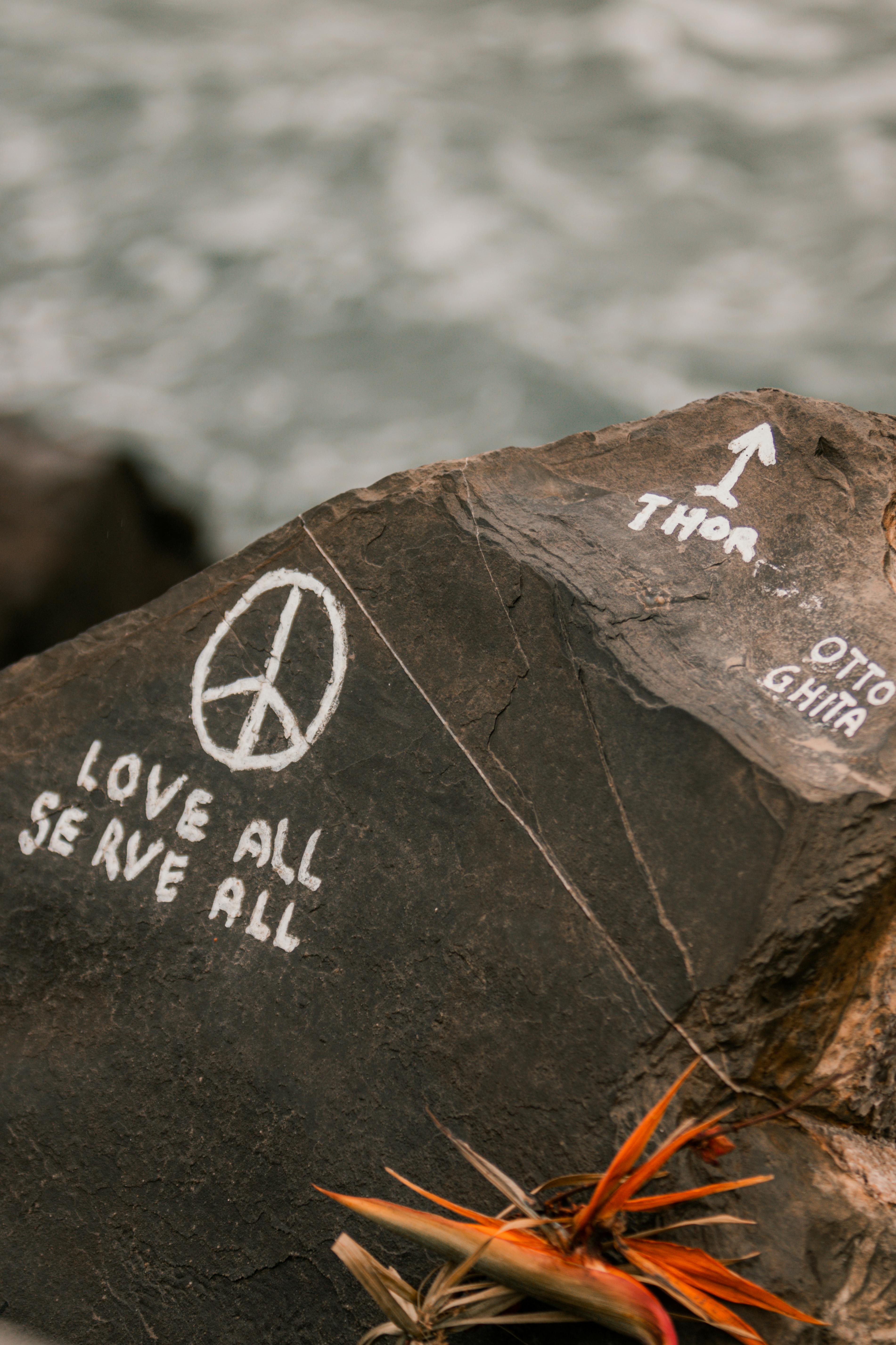 Peace Symbol and Texts Written on a Large Stone by a Sea · Free Stock Photo