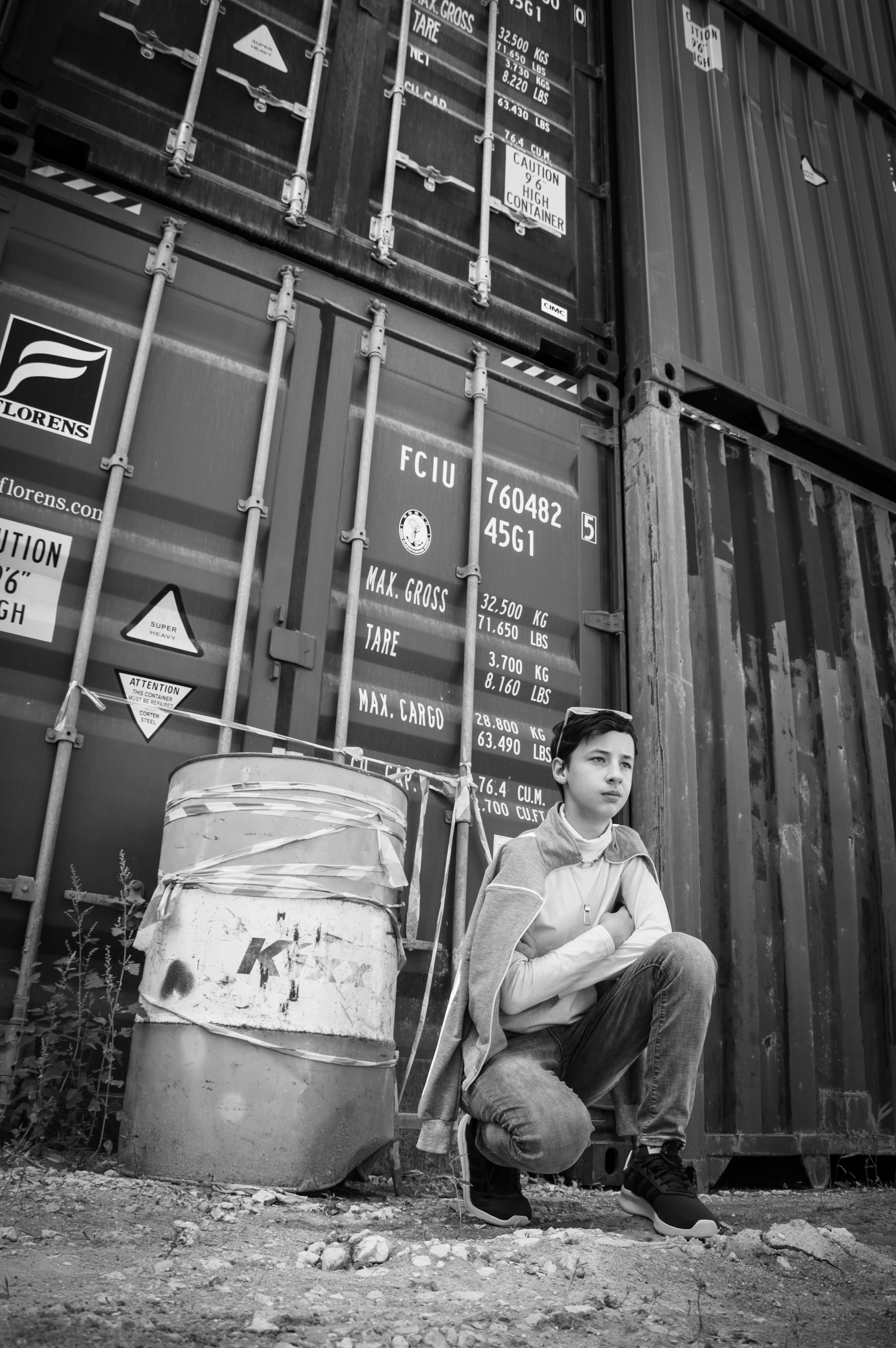 Boy with Crossed Arms Crouching by Containers · Free Stock Photo