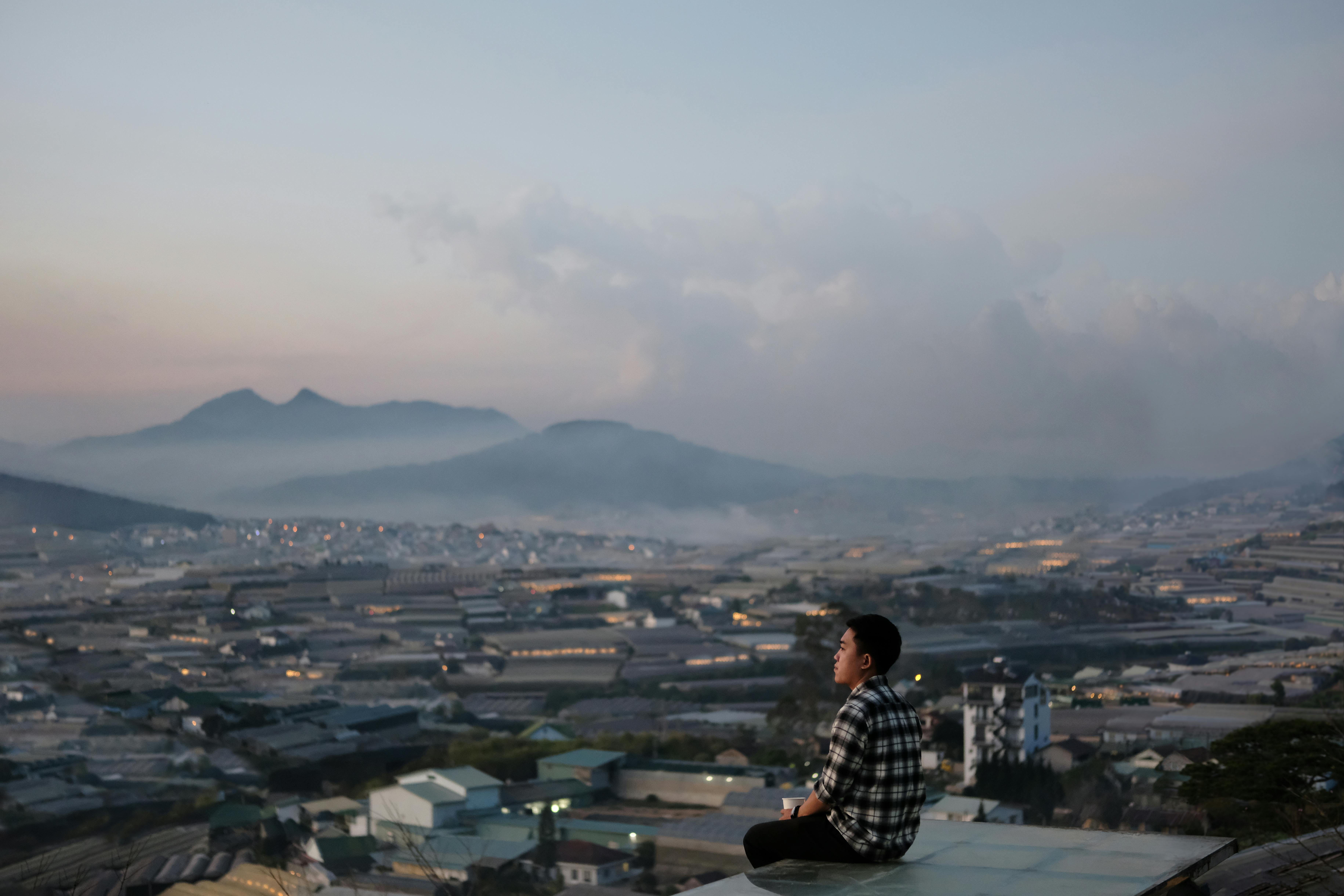 Man with Backpack Sitting on Rooftop of Skyscraper · Free Stock Photo