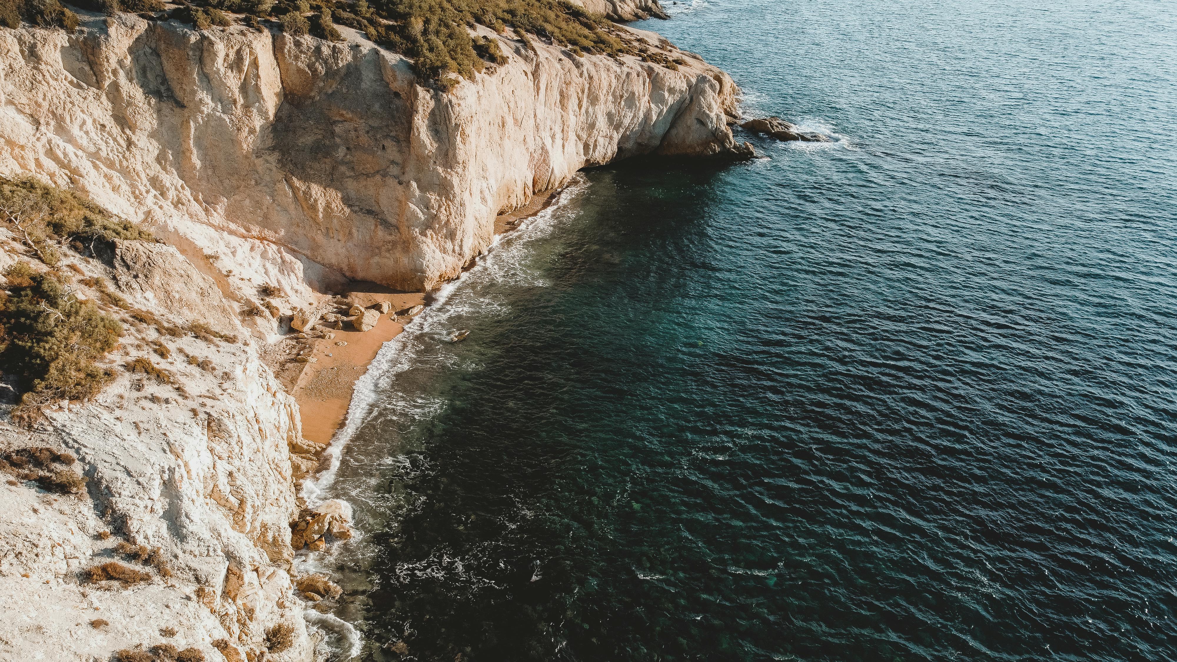 View of a Rocky Cliff and Small Empty Beach · Free Stock Photo
