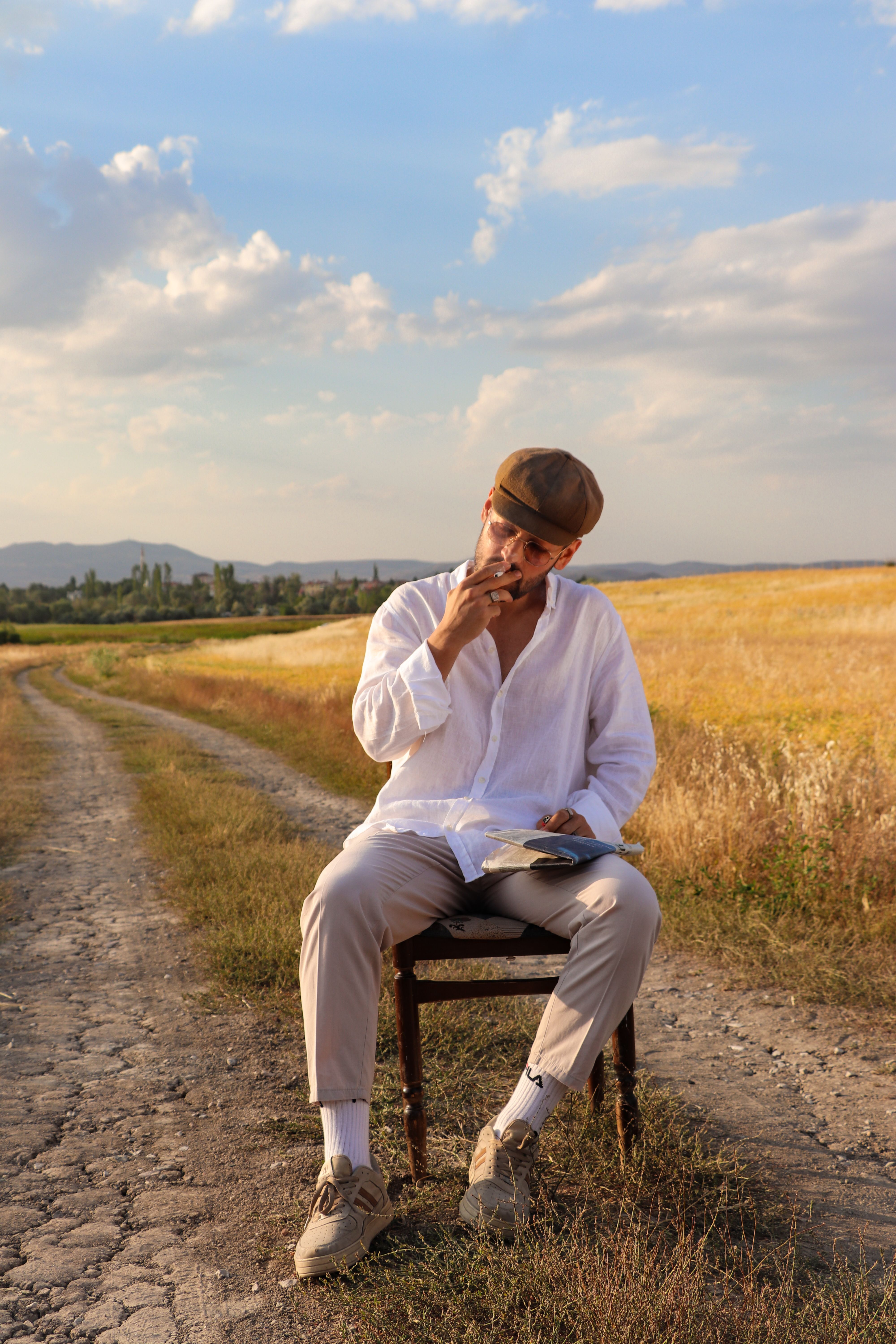 Man Smoking a Cigarette Sitting on a Country Road · Free Stock Photo