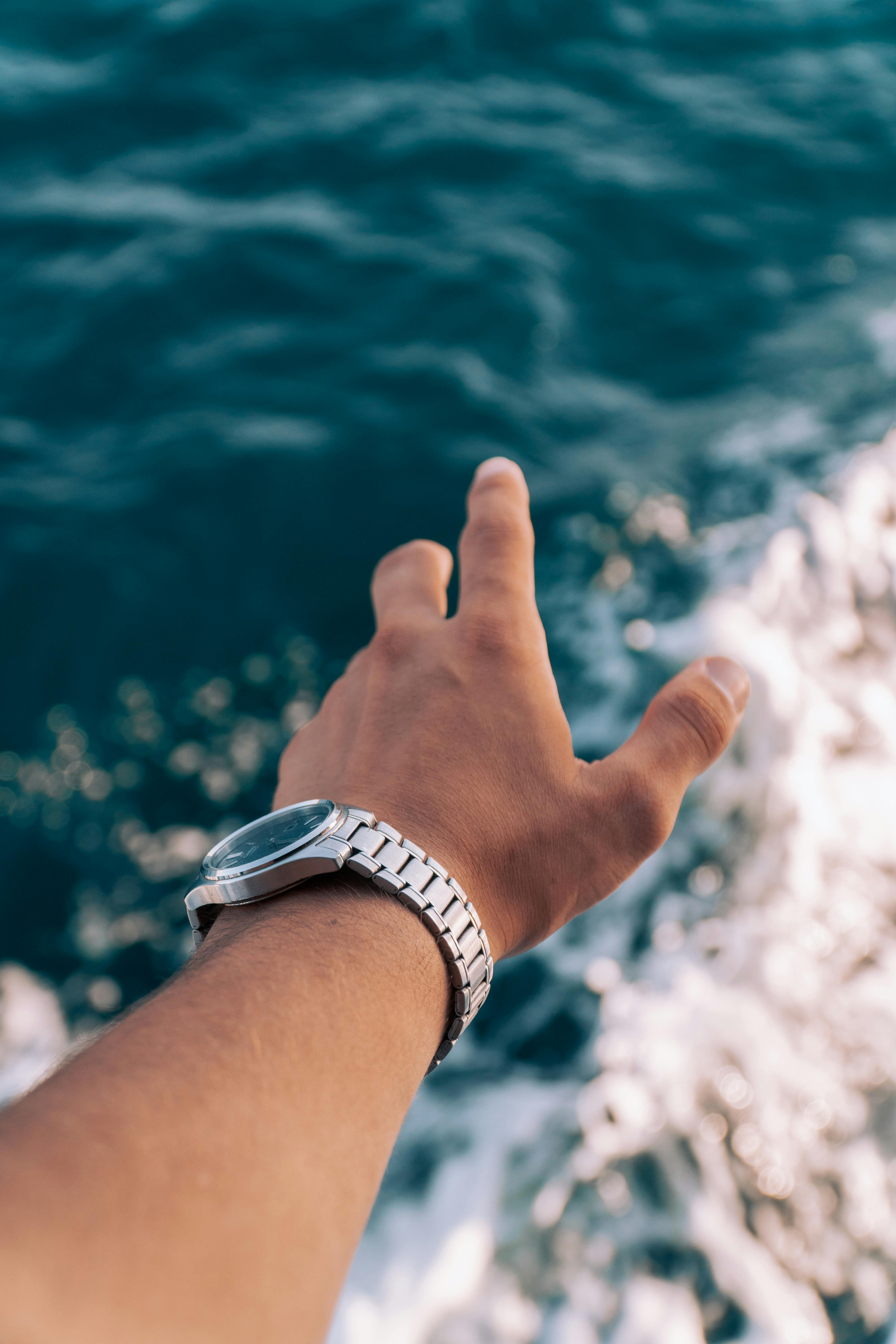 Man with Wristwatch Gesturing towards the Sea · Free Stock Photo