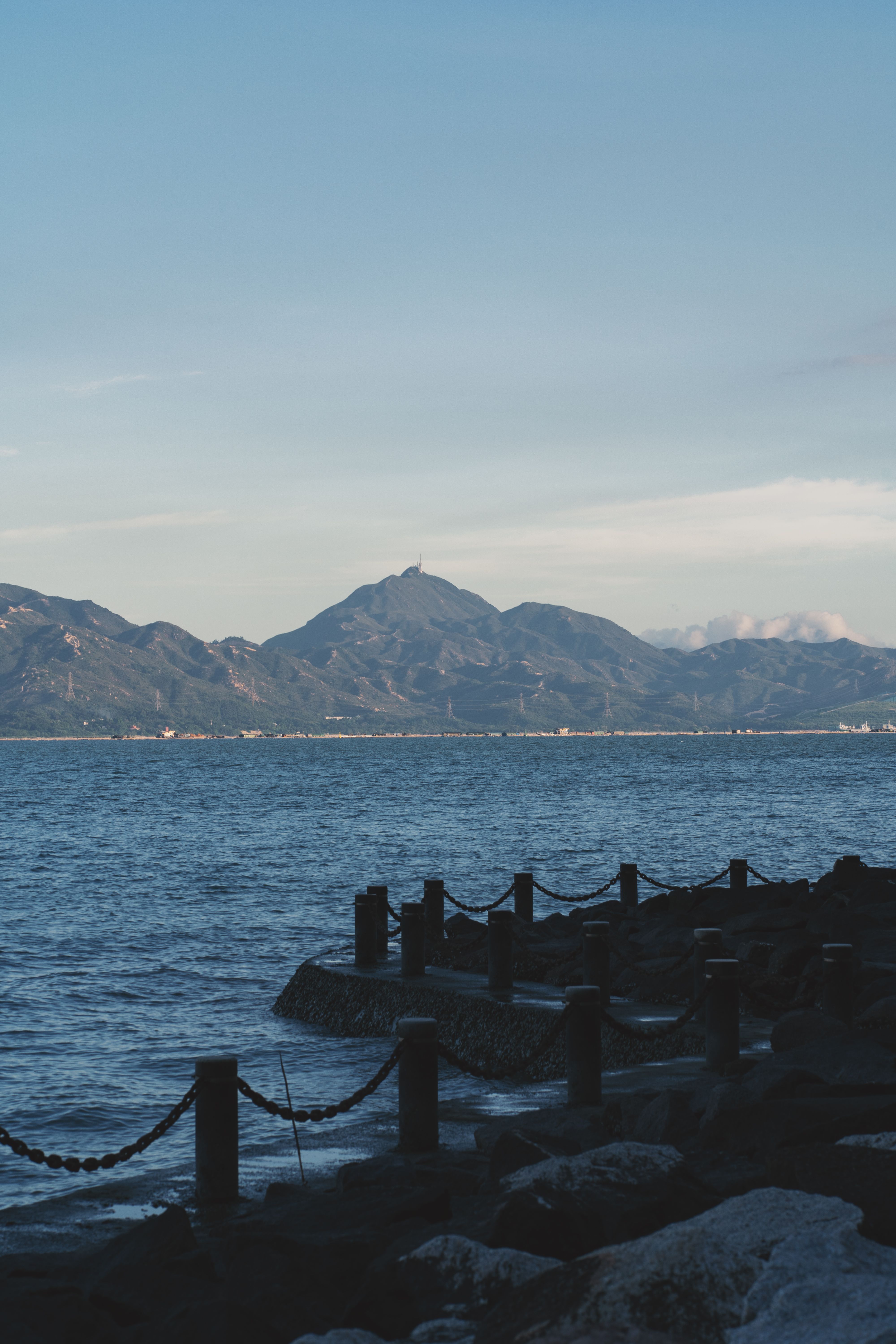 Pier with Barriers on Lakeshore and with Hills behind · Free Stock Photo