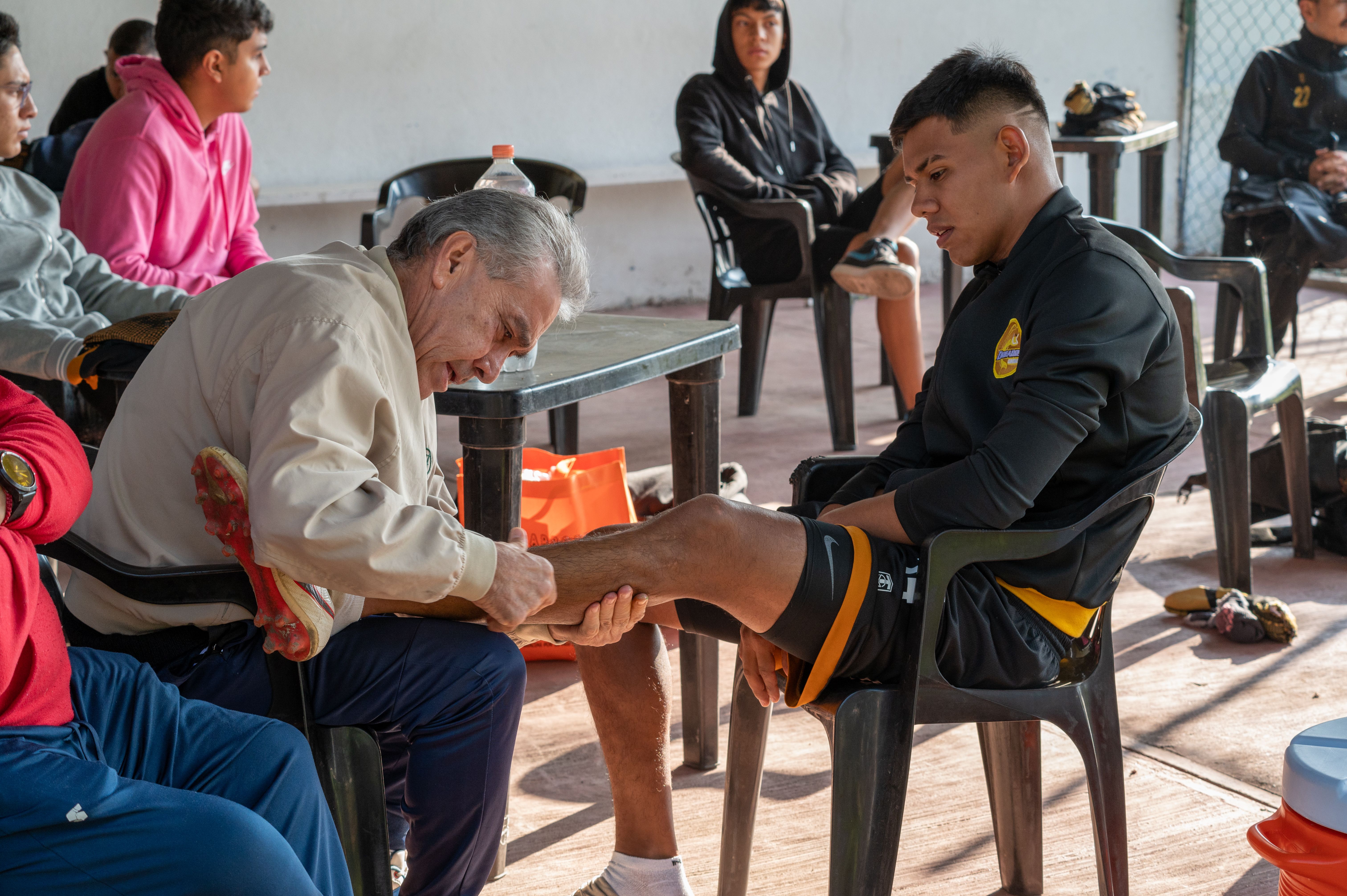 Senior Man Checking a Young Soccer Player Leg · Free Stock Photo
