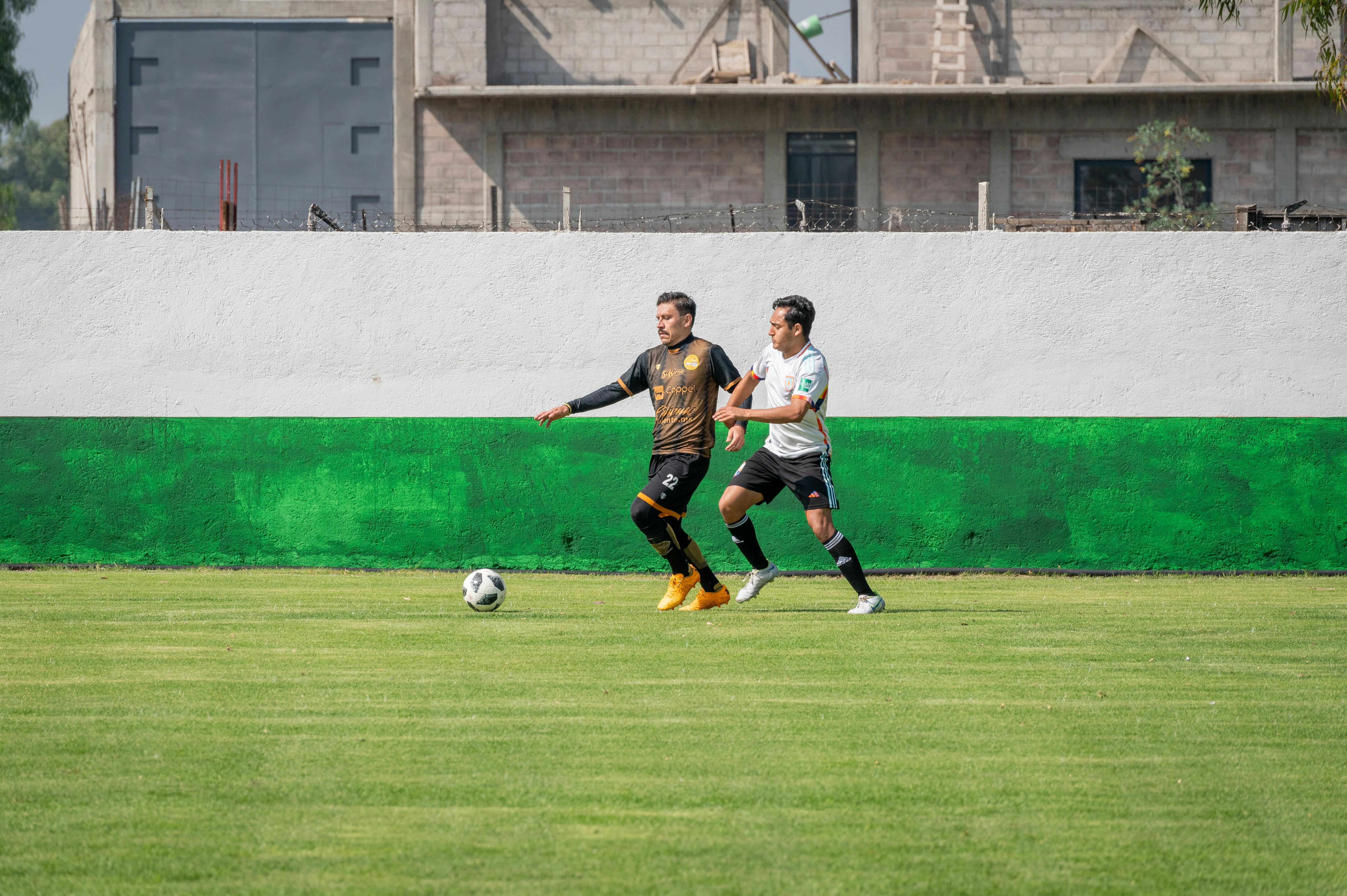 Two Rival Soccer Players Running for a Football · Free Stock Photo