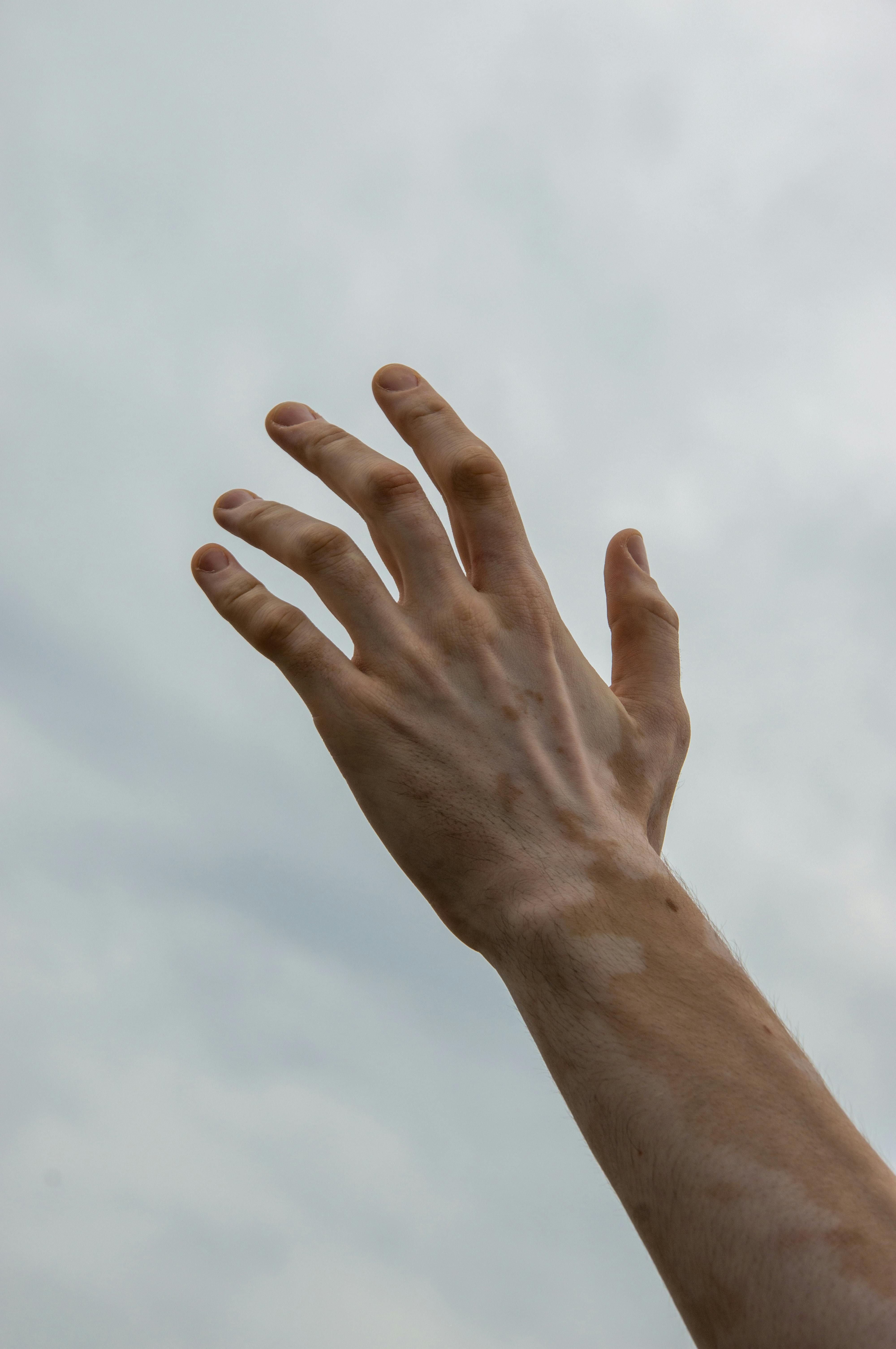 Close-up of a Raised Arm and a Hand Sign · Free Stock Photo