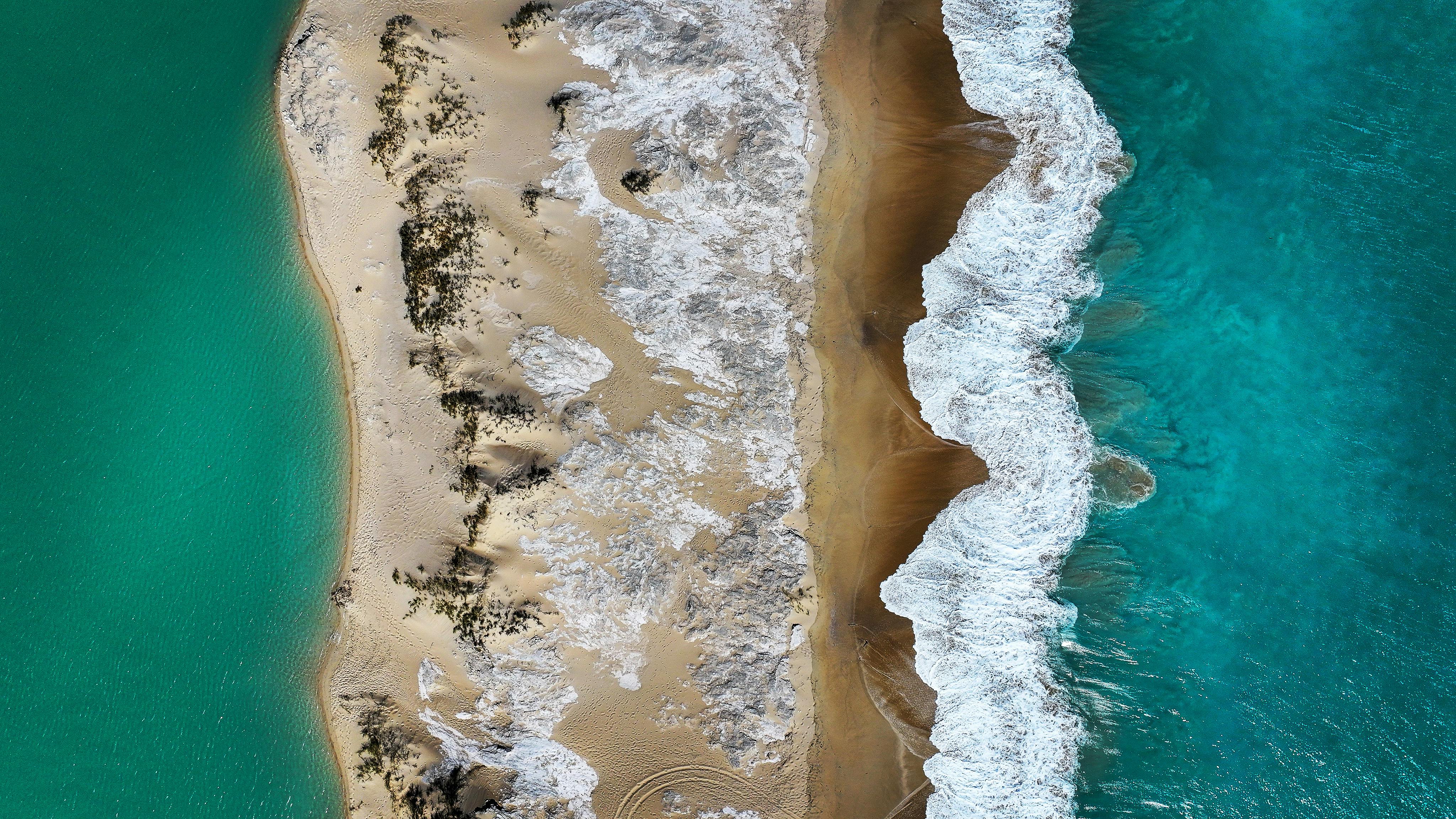 Aerial Photo of a Waves Rolling on a Thin Beach Strip · Free Stock Photo