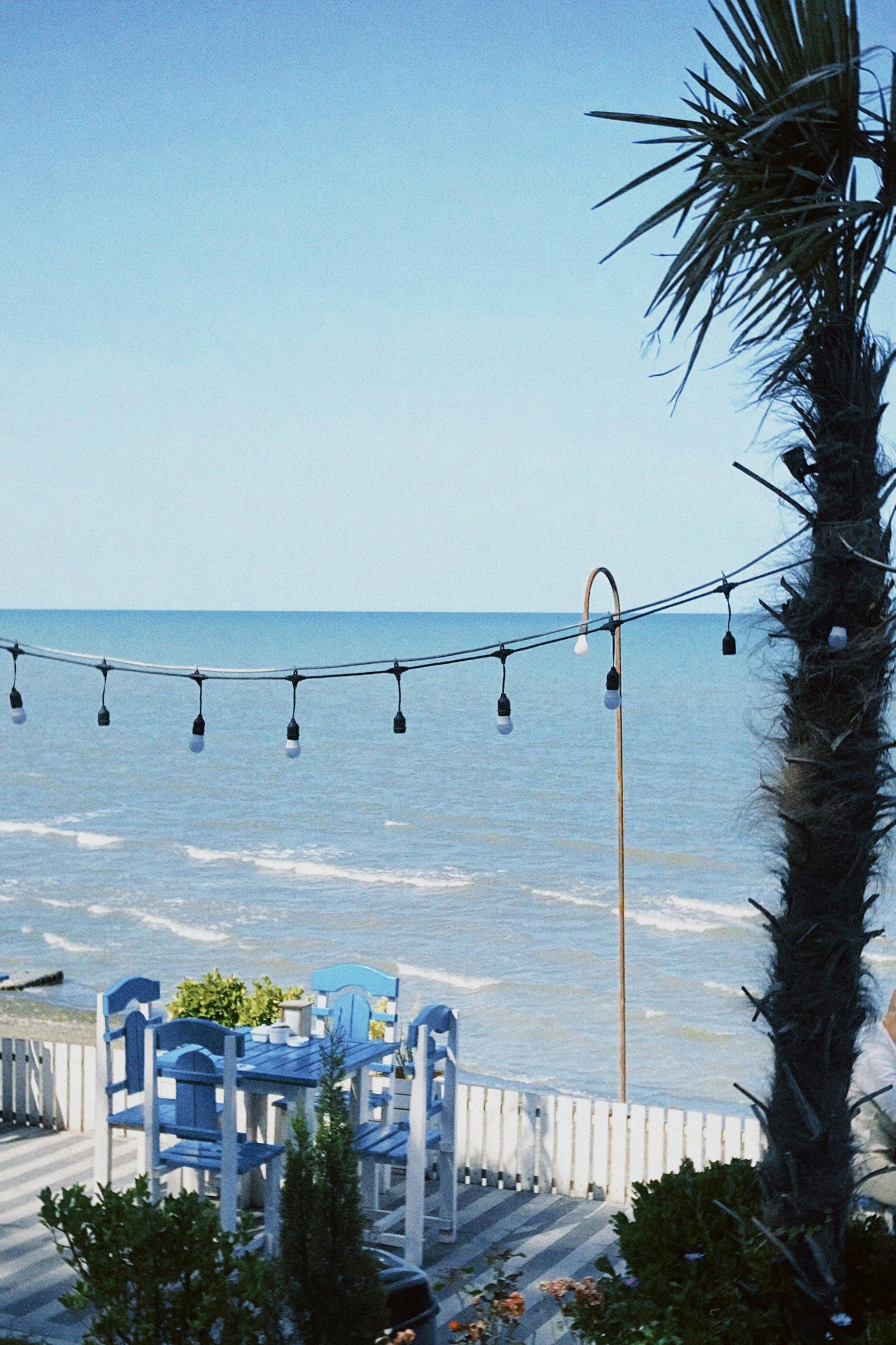 Chairs and Table on Restaurant Patio by Ocean Shore · Free Stock Photo