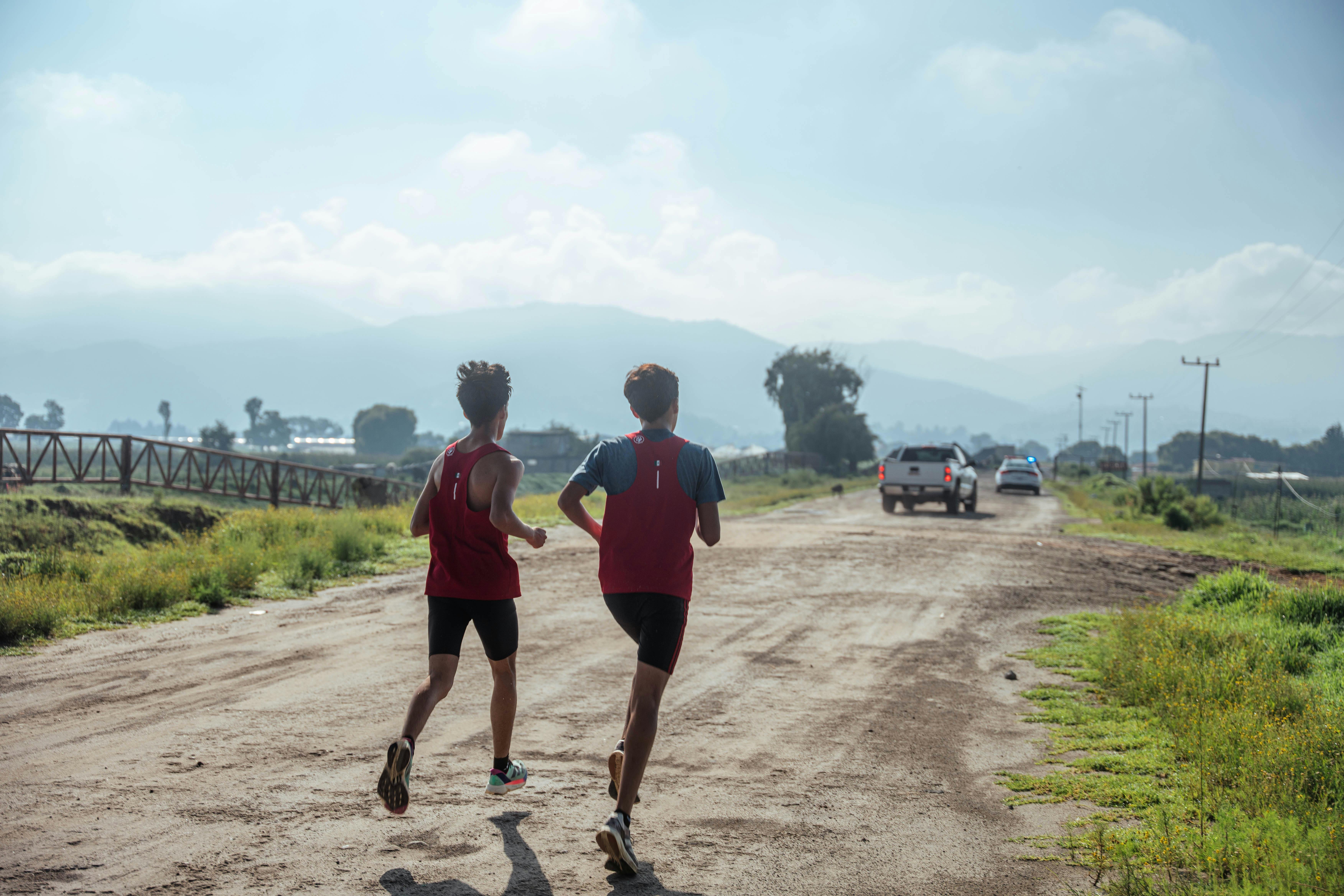 Backs of Men Running a Marathon in the Countryside · Free Stock Photo