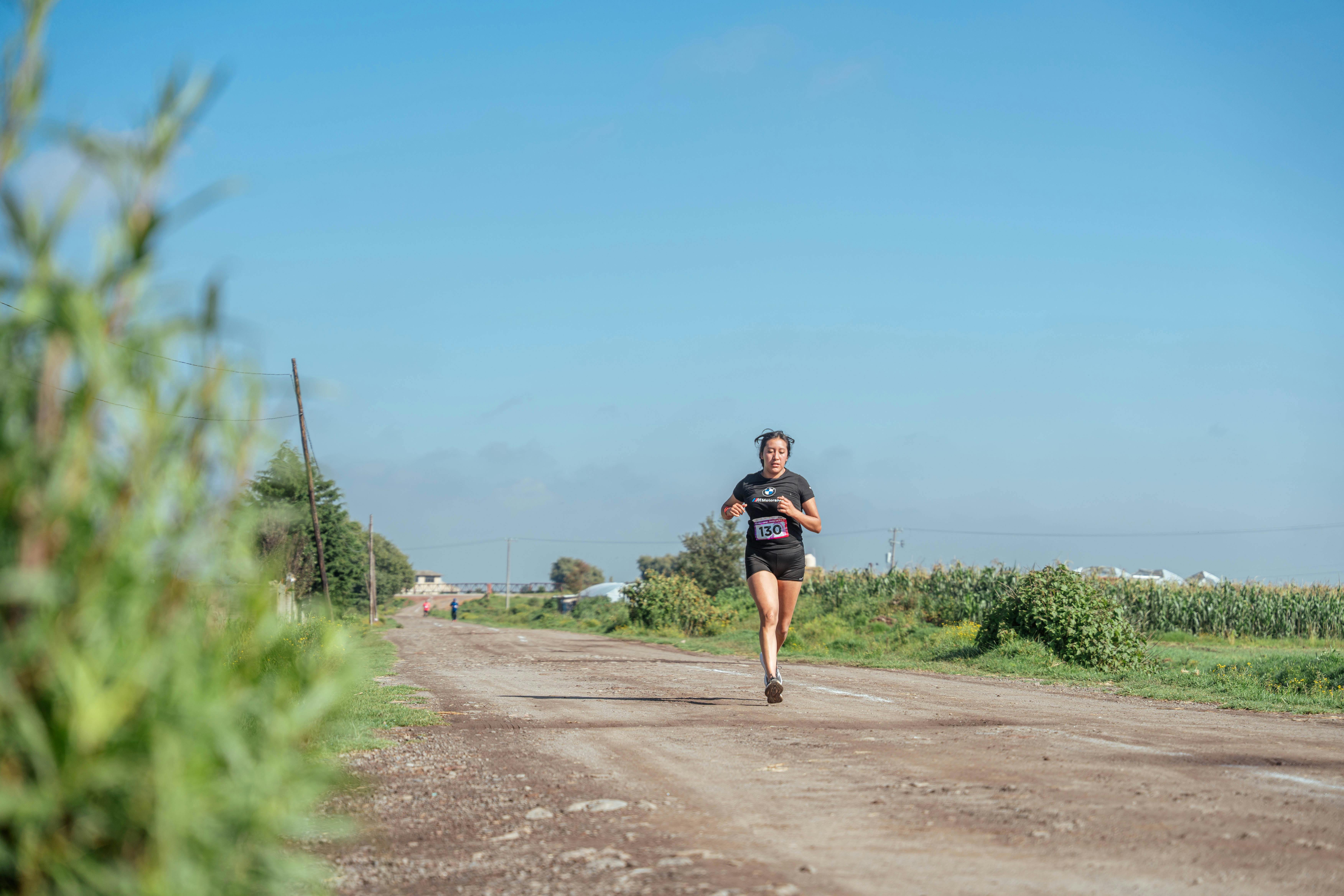 Woman Running Down the Road in a Marathon · Free Stock Photo