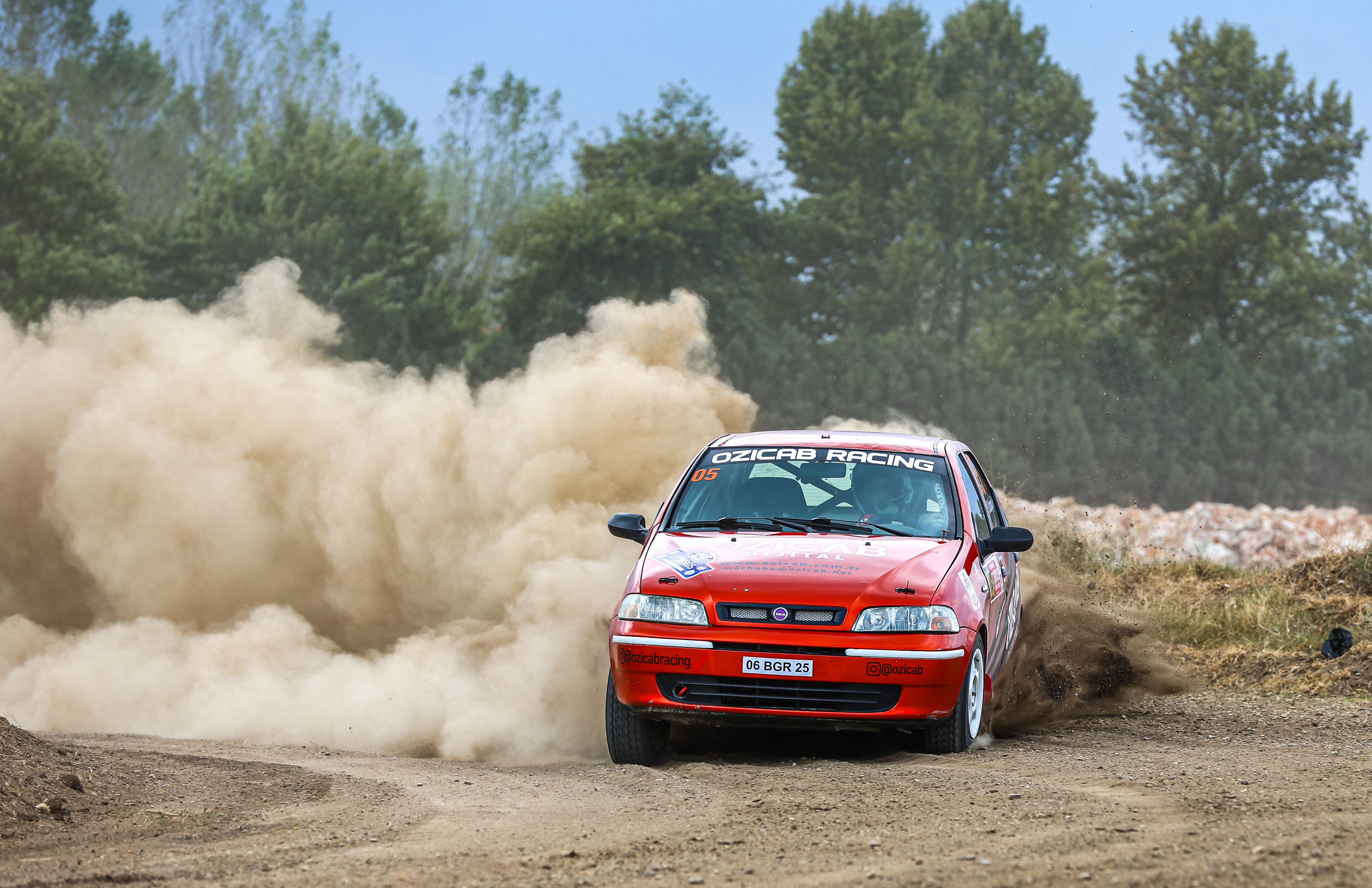 A red car driving through a dirt field · Free Stock Photo