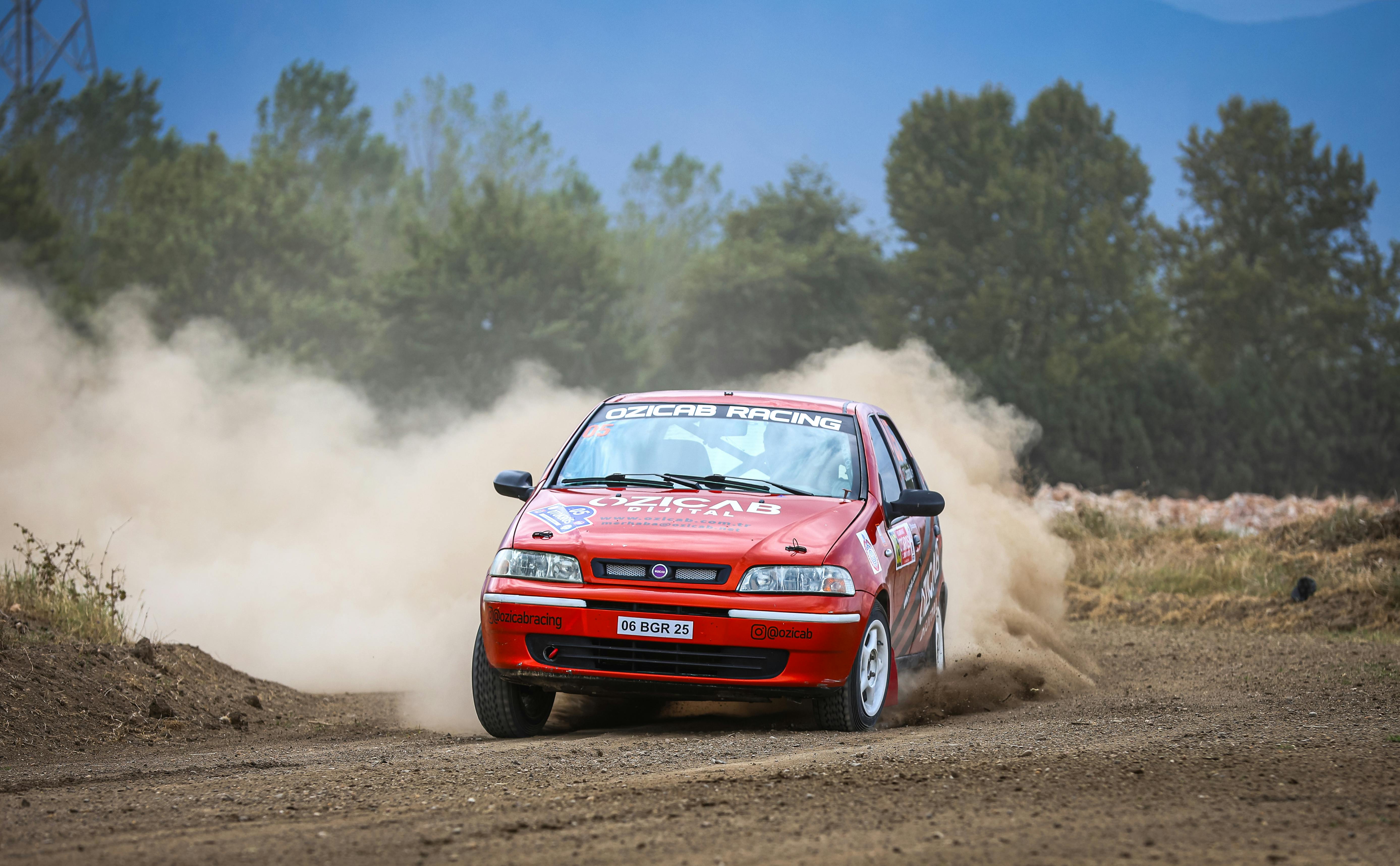 A red car driving on a dirt road · Free Stock Photo