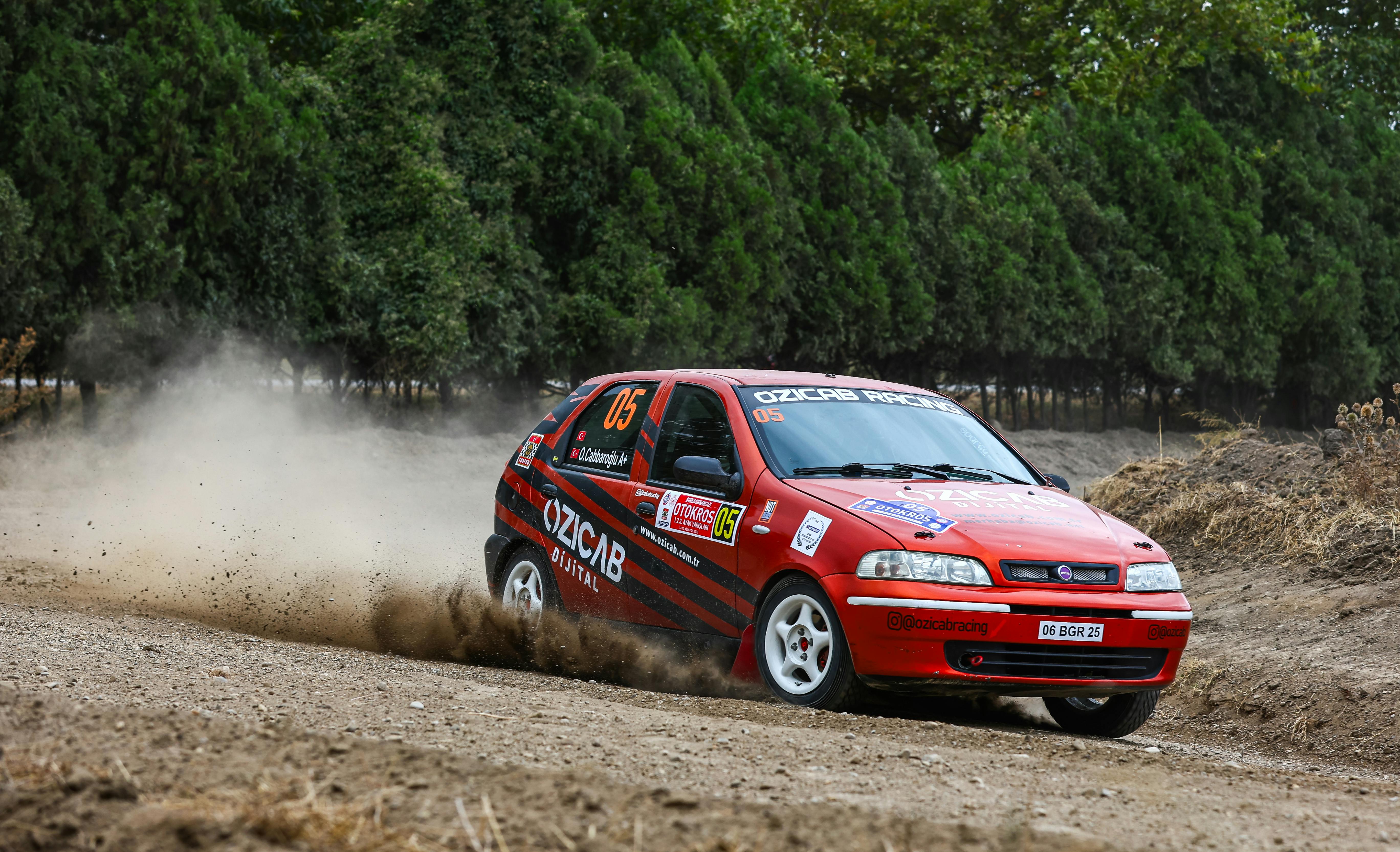 A red car driving on dirt in the middle of a field · Free Stock Photo