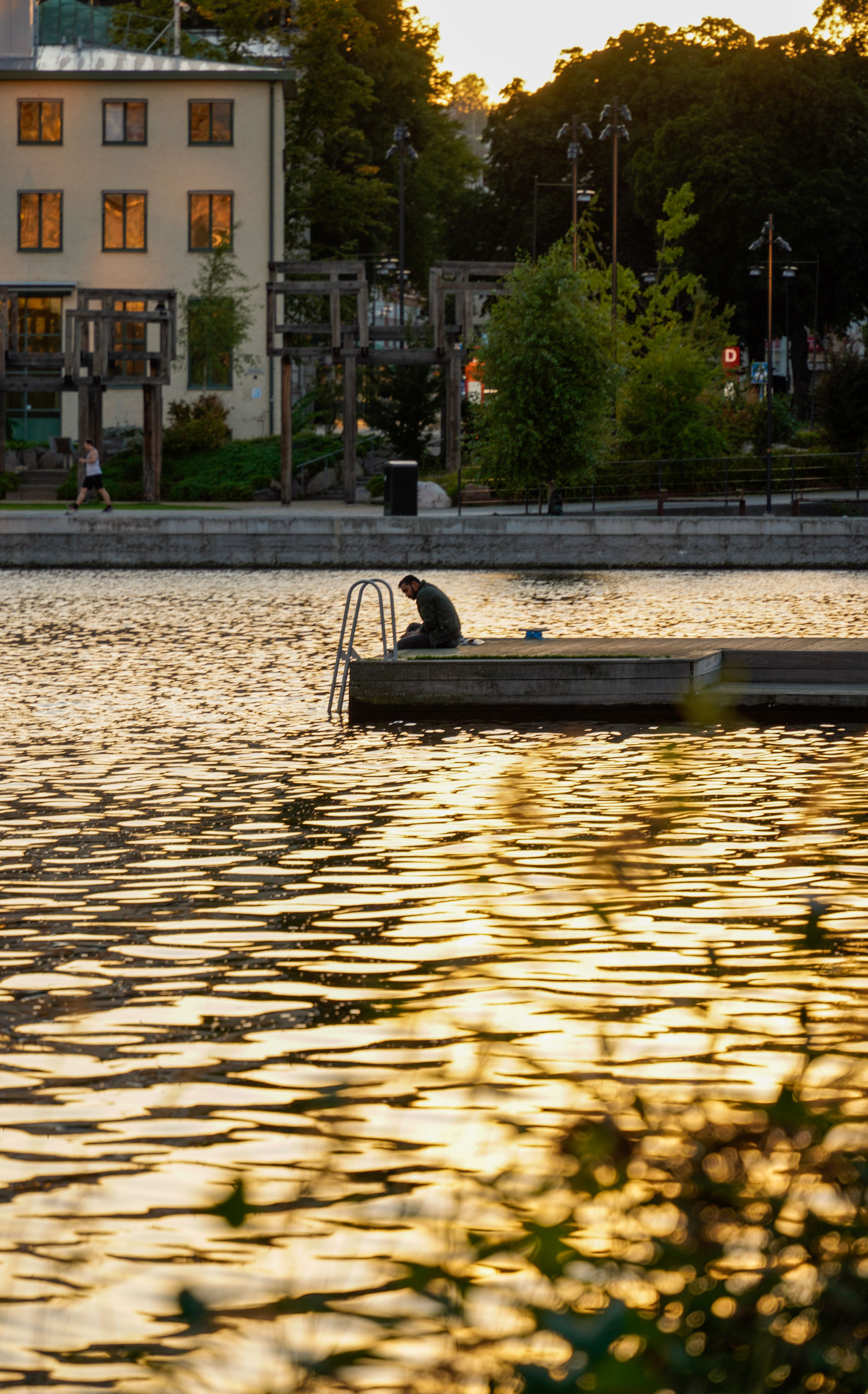 Man Sitting on Pier in Town at Sunset · Free Stock Photo