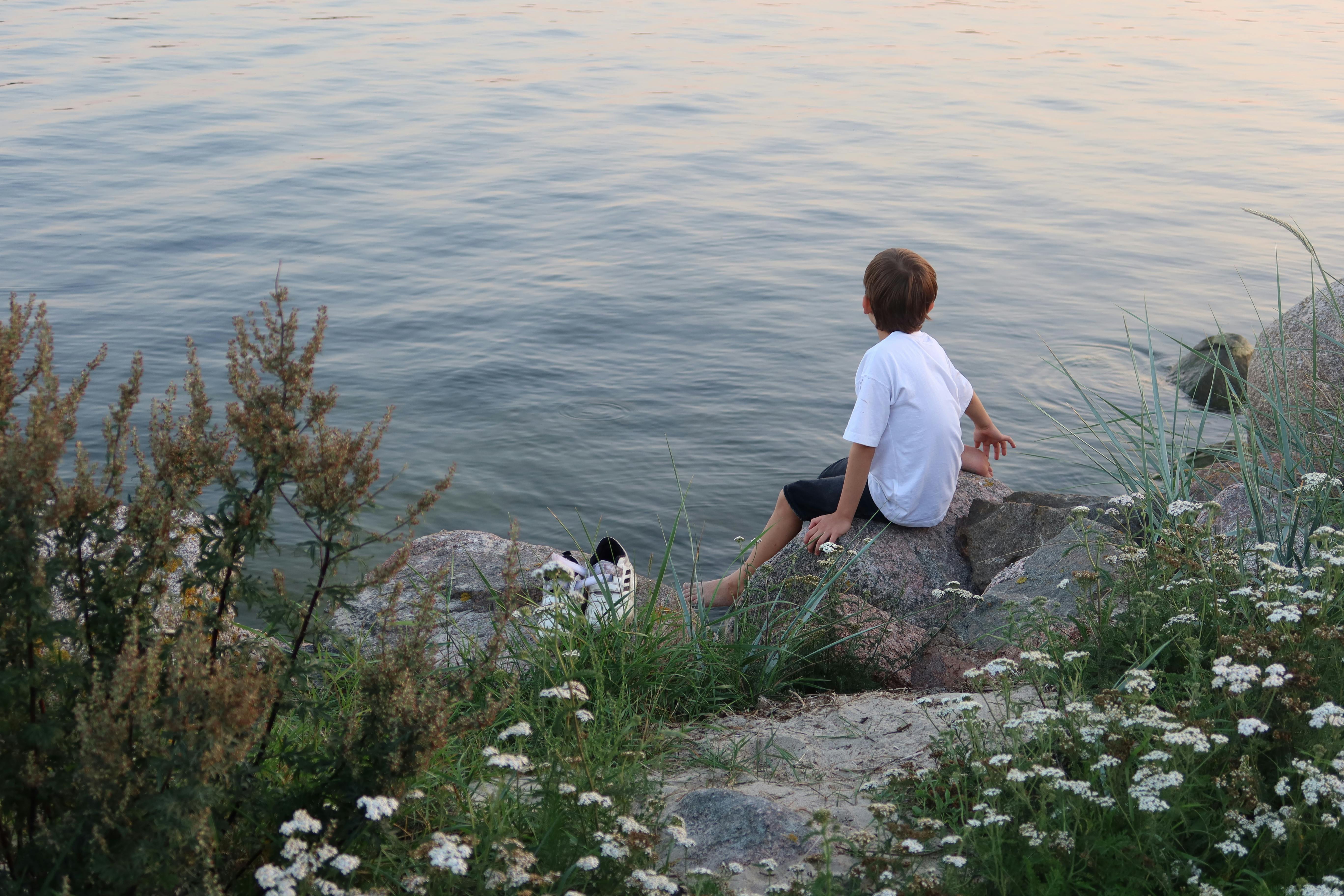 Boy Sitting on Lakeshore · Free Stock Photo