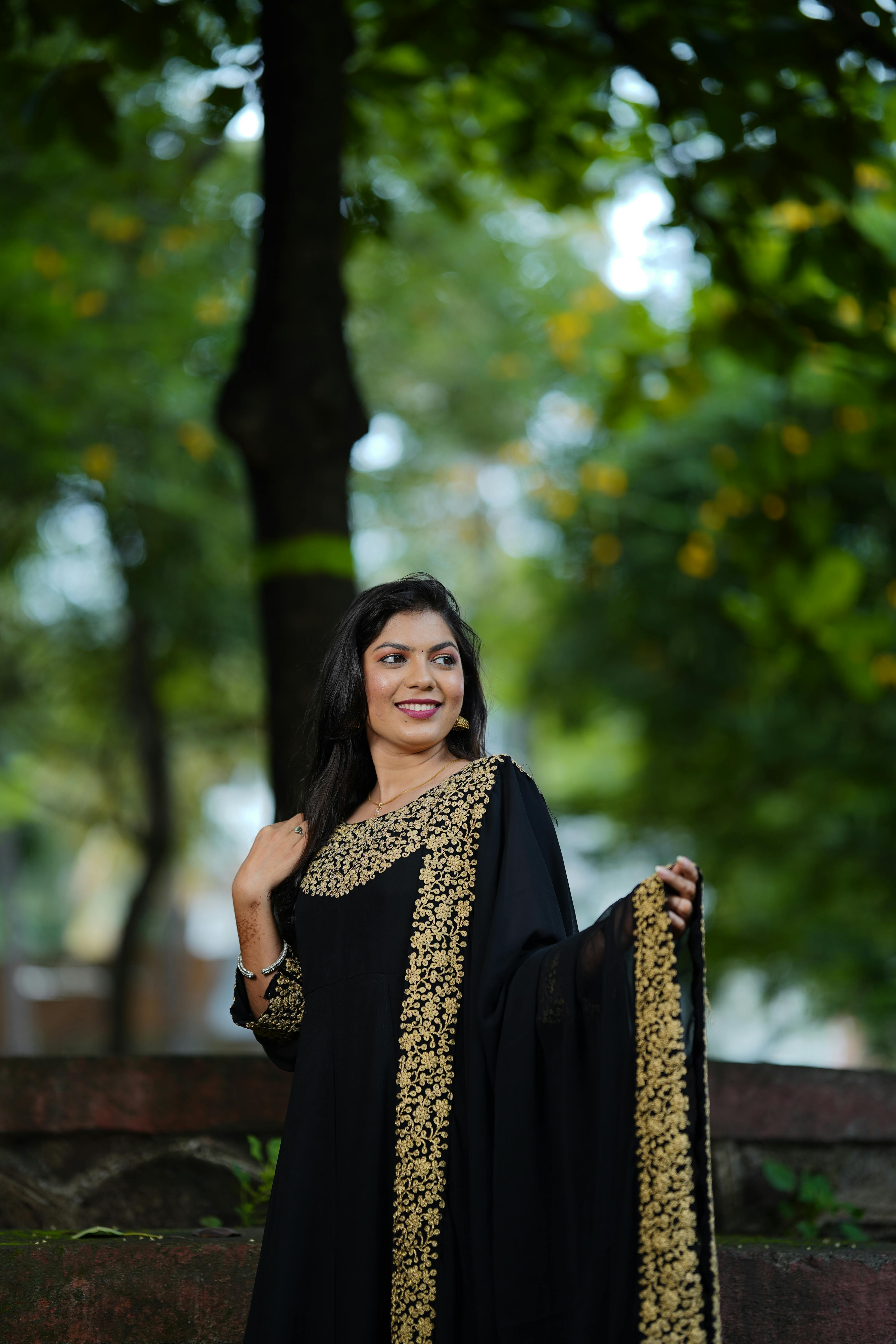 Young Woman in a Traditional Gown Standing by the Shrub in the Garden and Smiling · Free Stock Photo