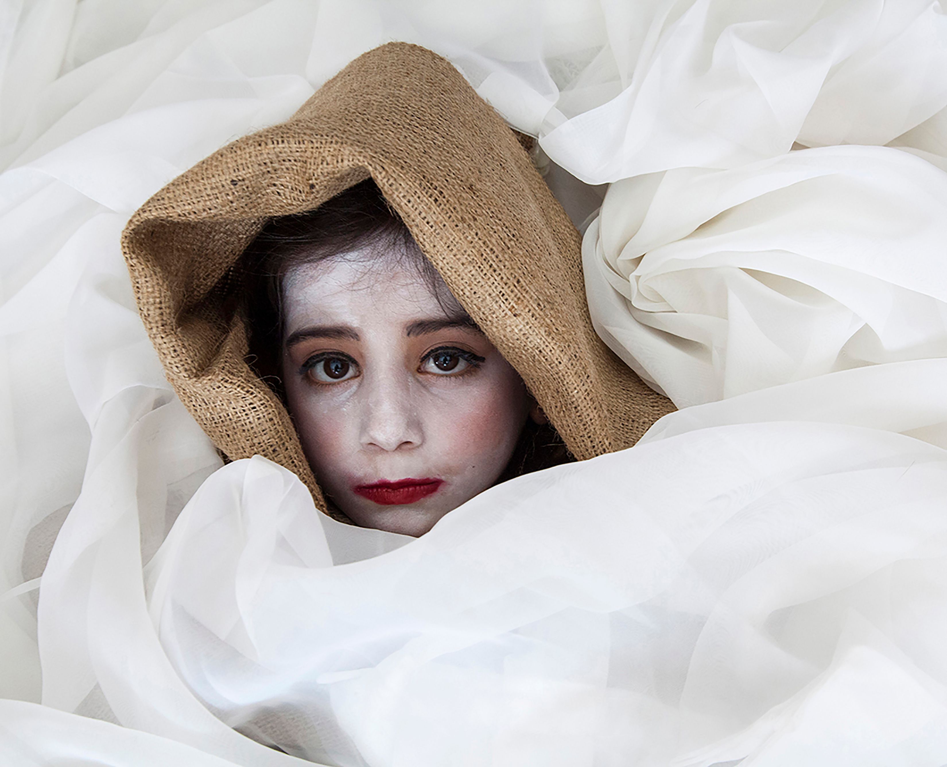 A Child with a White Painted Face between Tulle Fabric · Free Stock Photo
