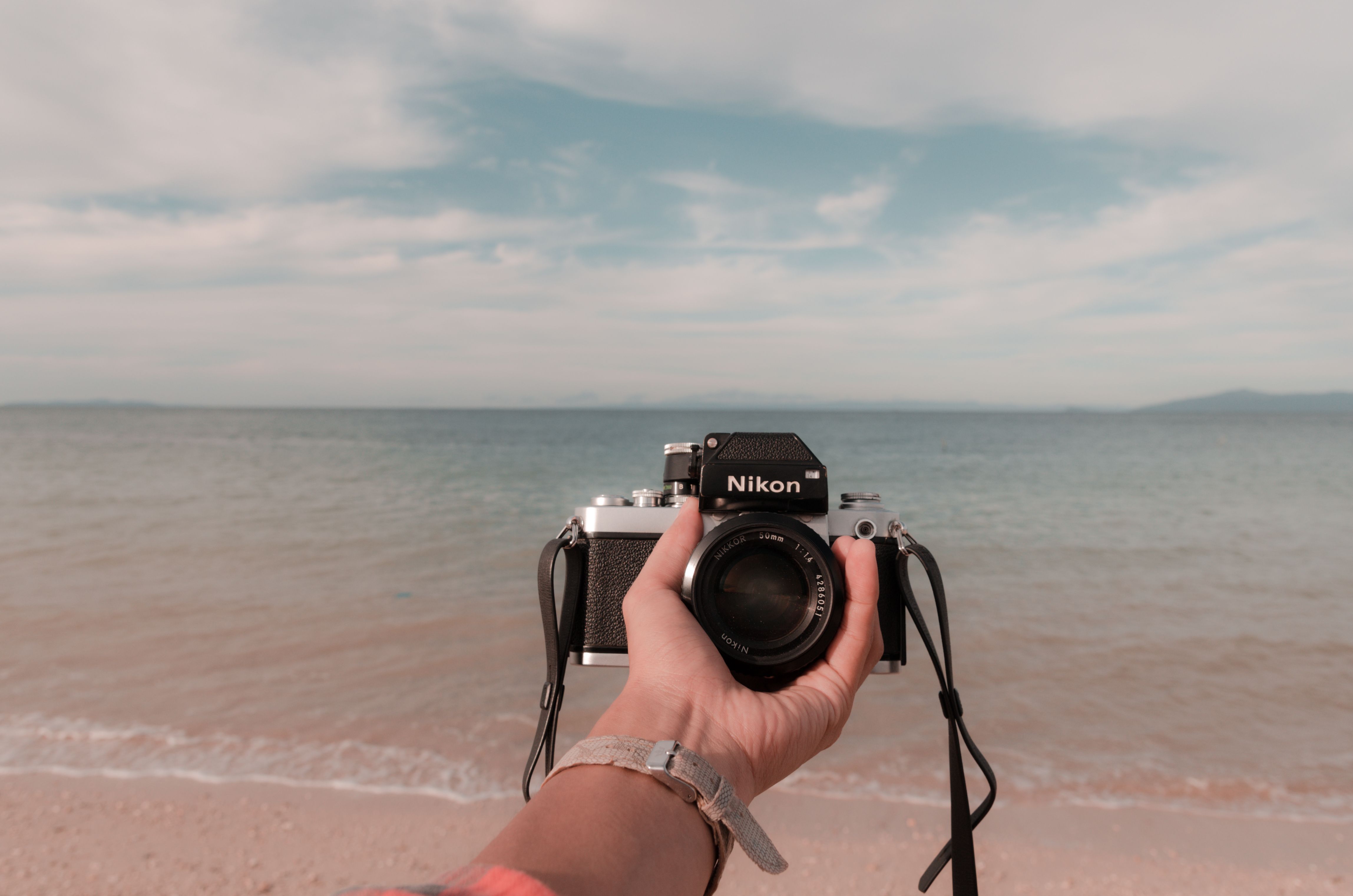 Hand Holding Camera over Sea Shore · Free Stock Photo