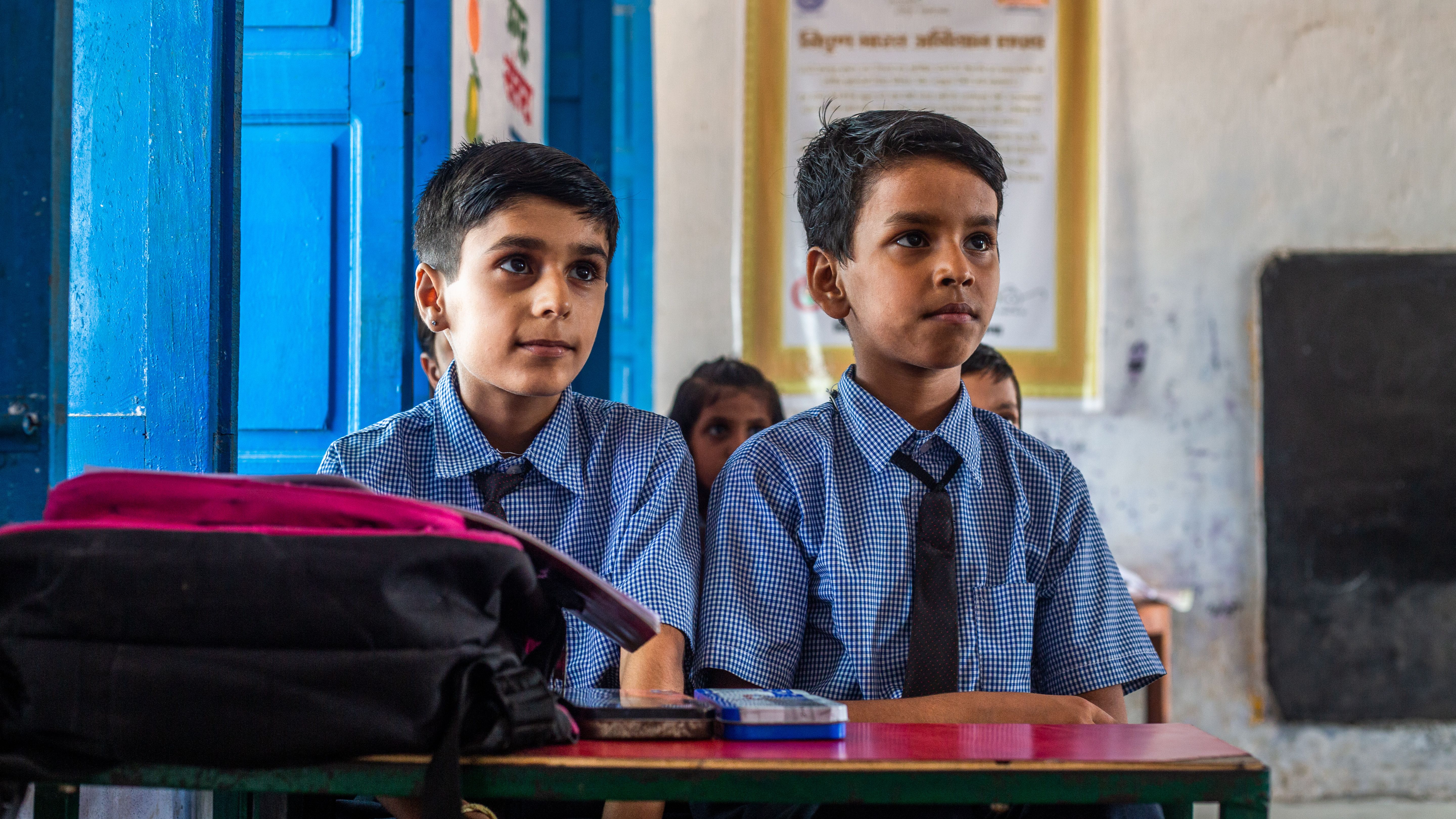 Two boys in school uniforms sitting at desks · Free Stock Photo