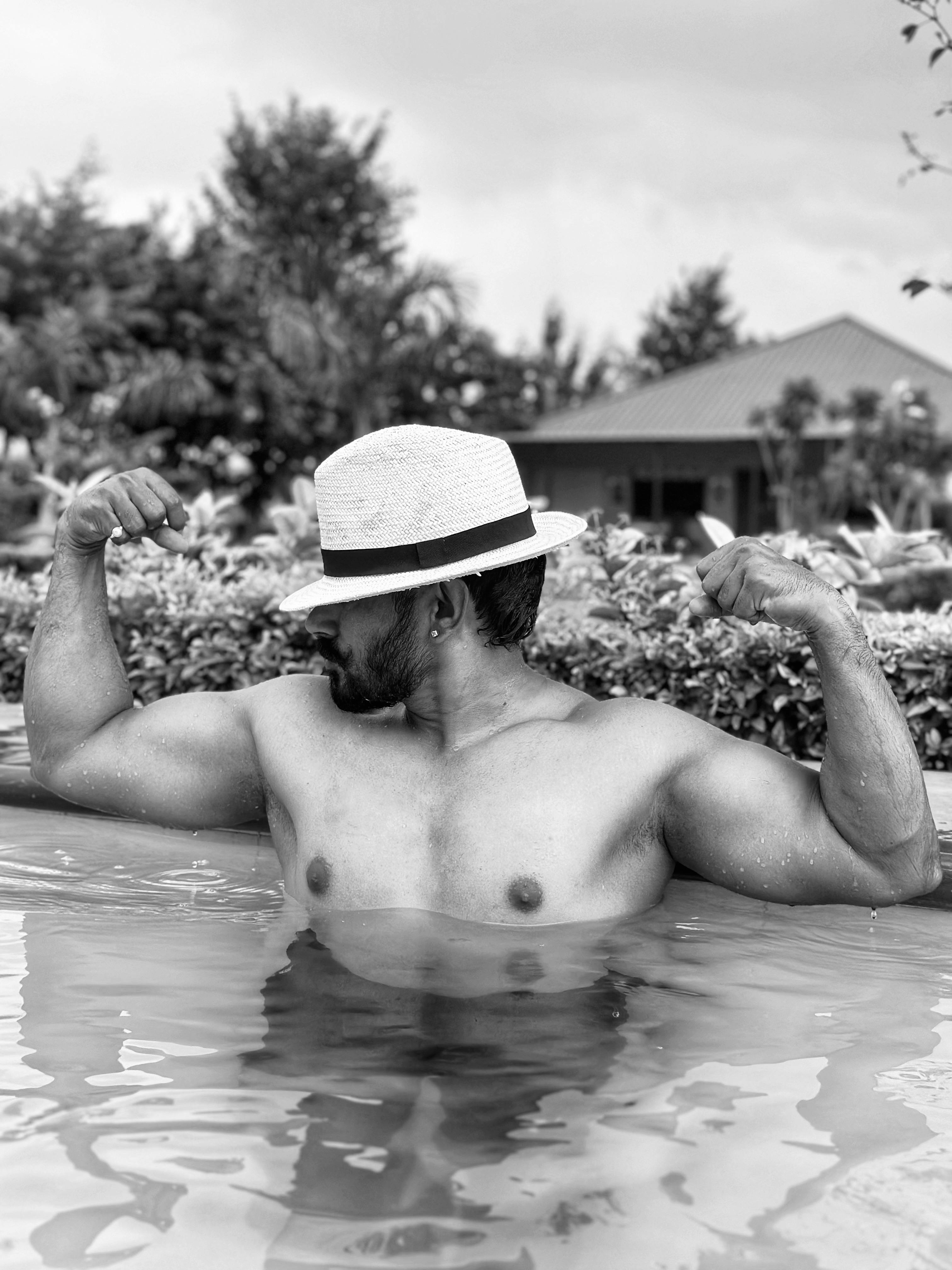 Muscular Man Wearing a Fedora Relaxing in a Pool · Free Stock Photo
