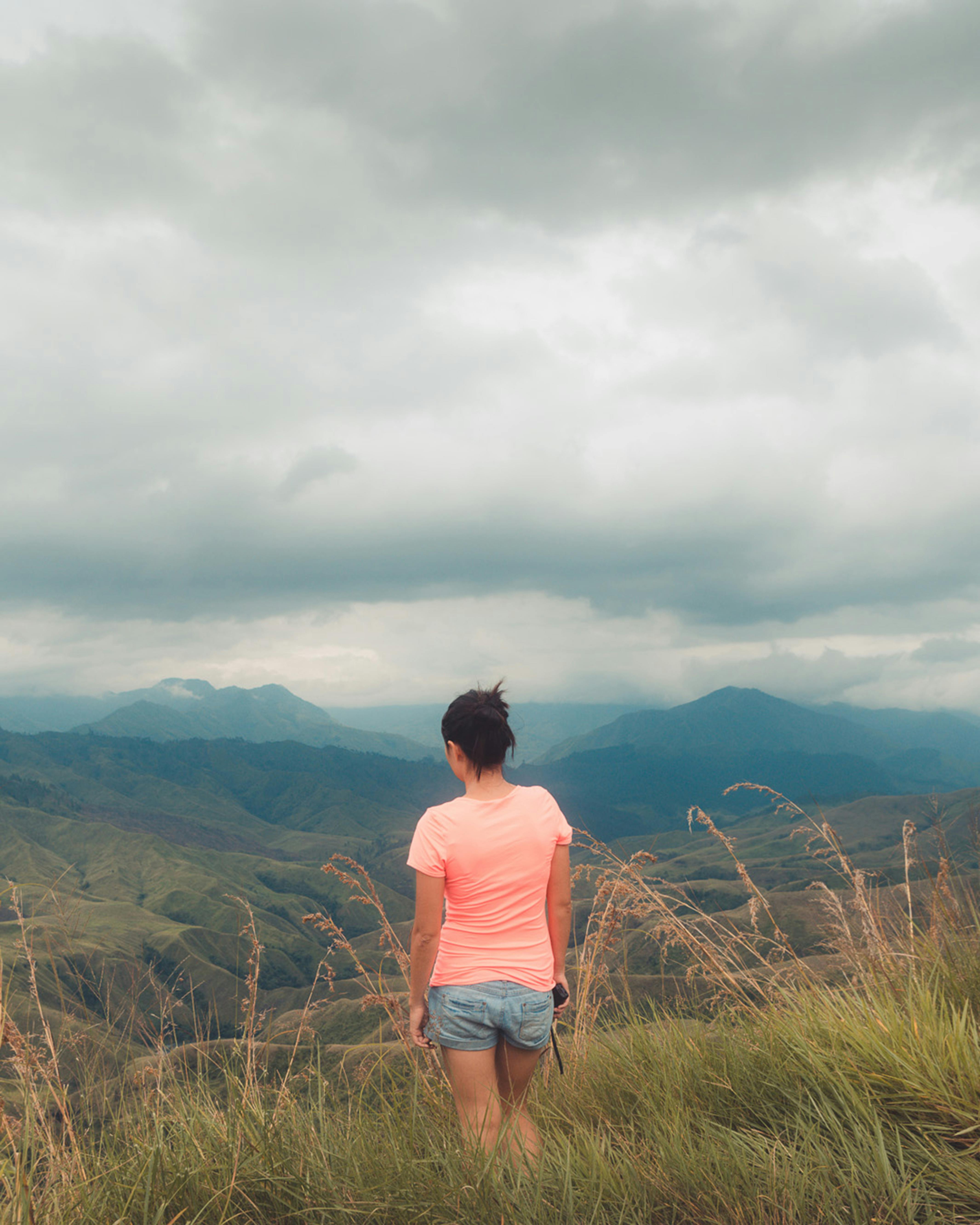 Back View of a Woman Standing on a Mountain Peak and Looking at the ...