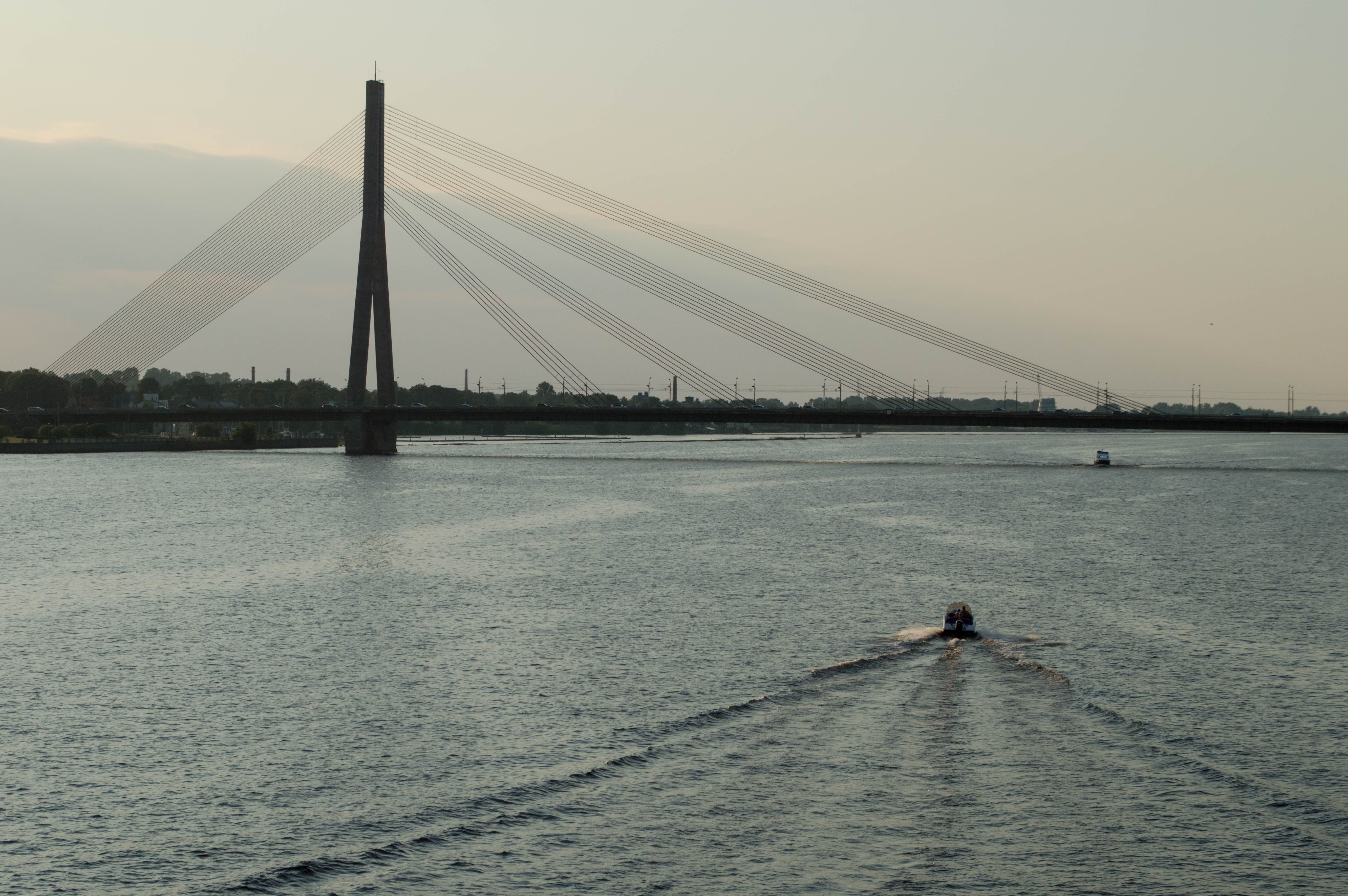 A boat is traveling across the water with a bridge in the background ...