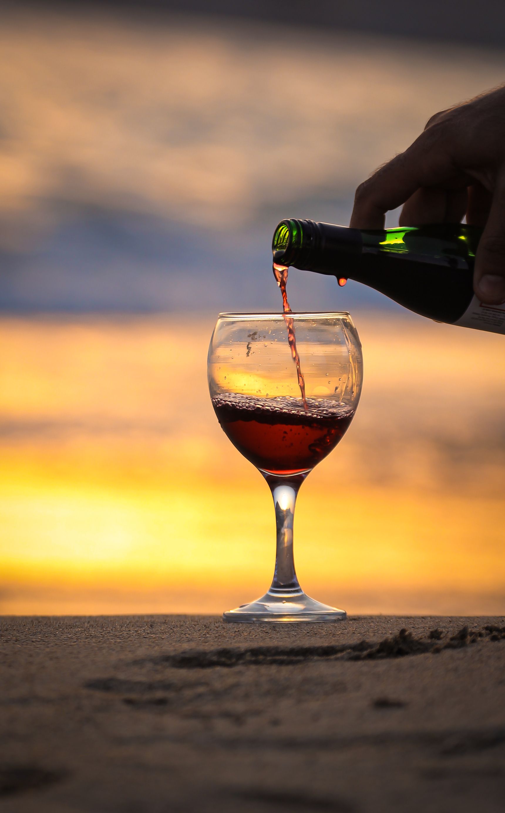 Person Pouring Wine in a Glass Standing on Beach Sand at Sunset · Free ...