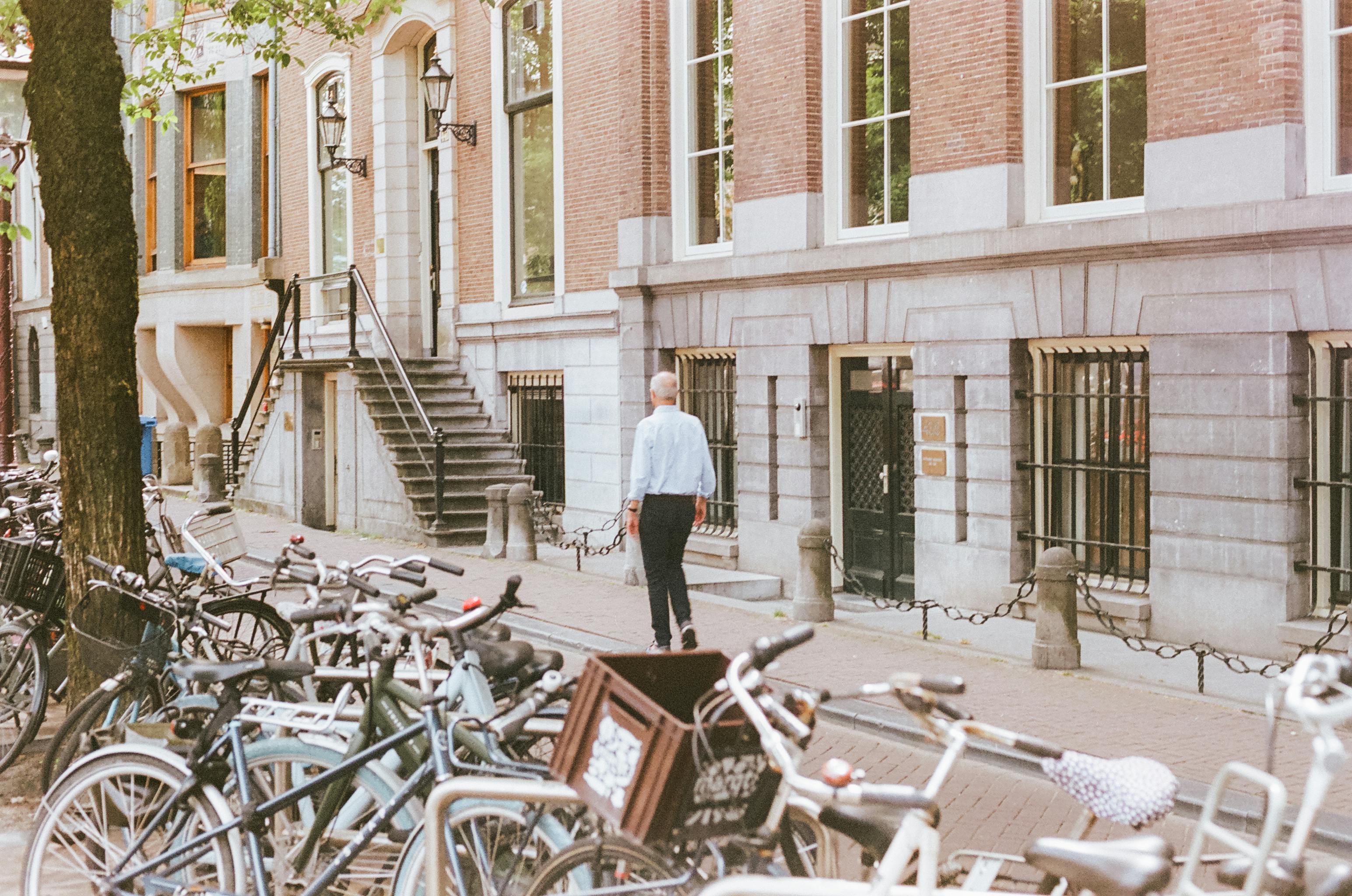 Man Walking behind Bikes on Sidewalk · Free Stock Photo