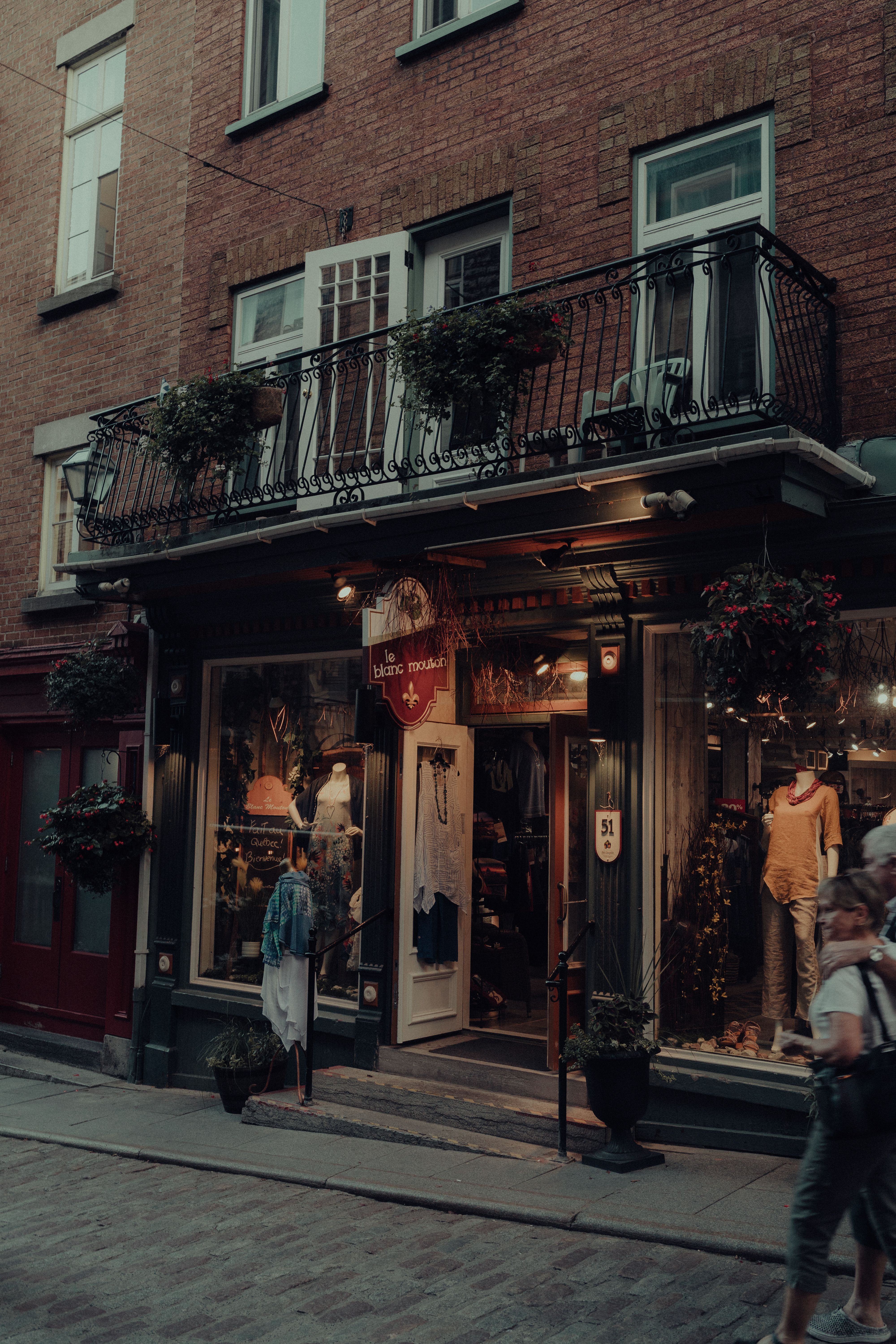 A store front on a cobblestone street with people walking by · Free ...