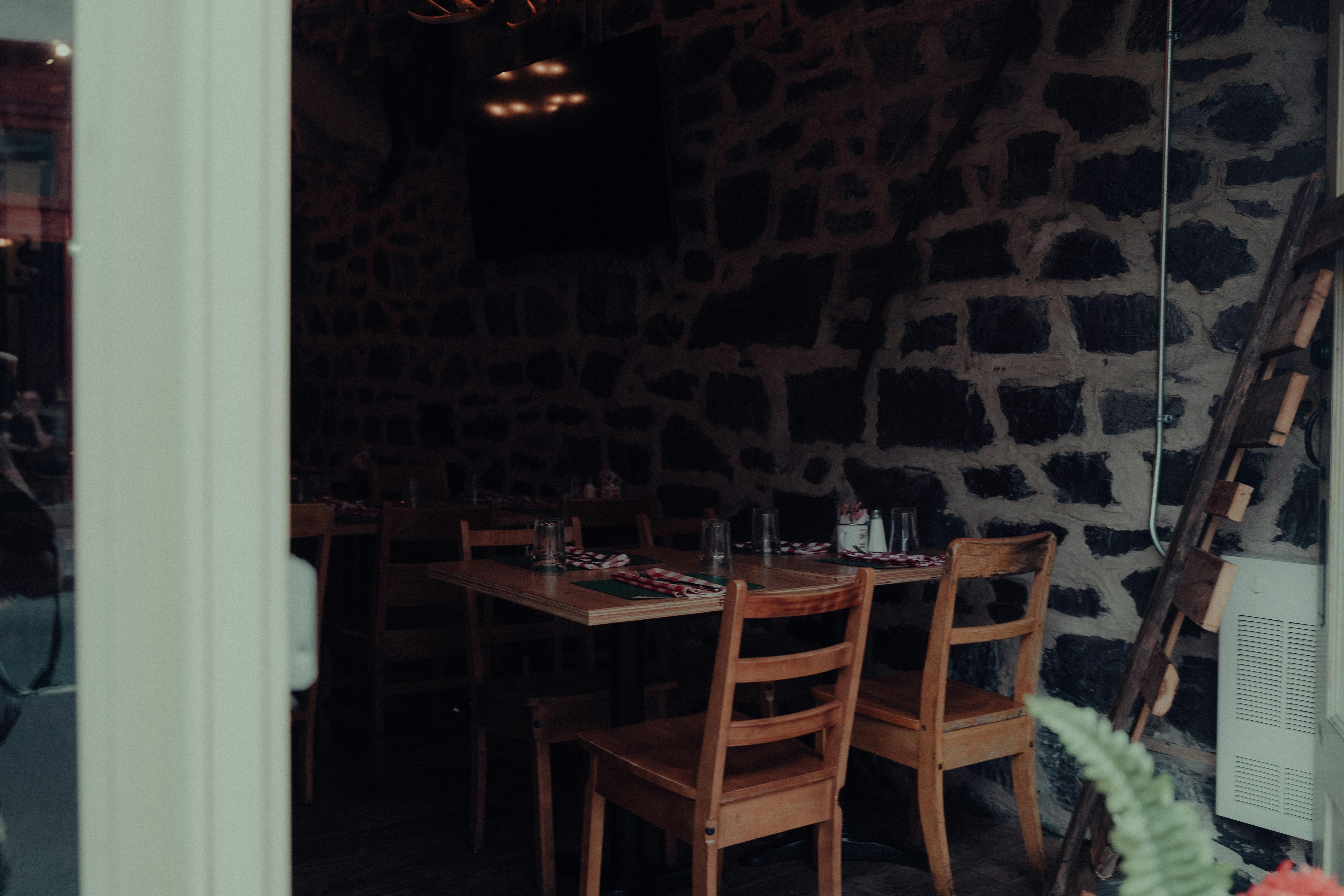 A restaurant with a stone wall and wooden tables · Free Stock Photo