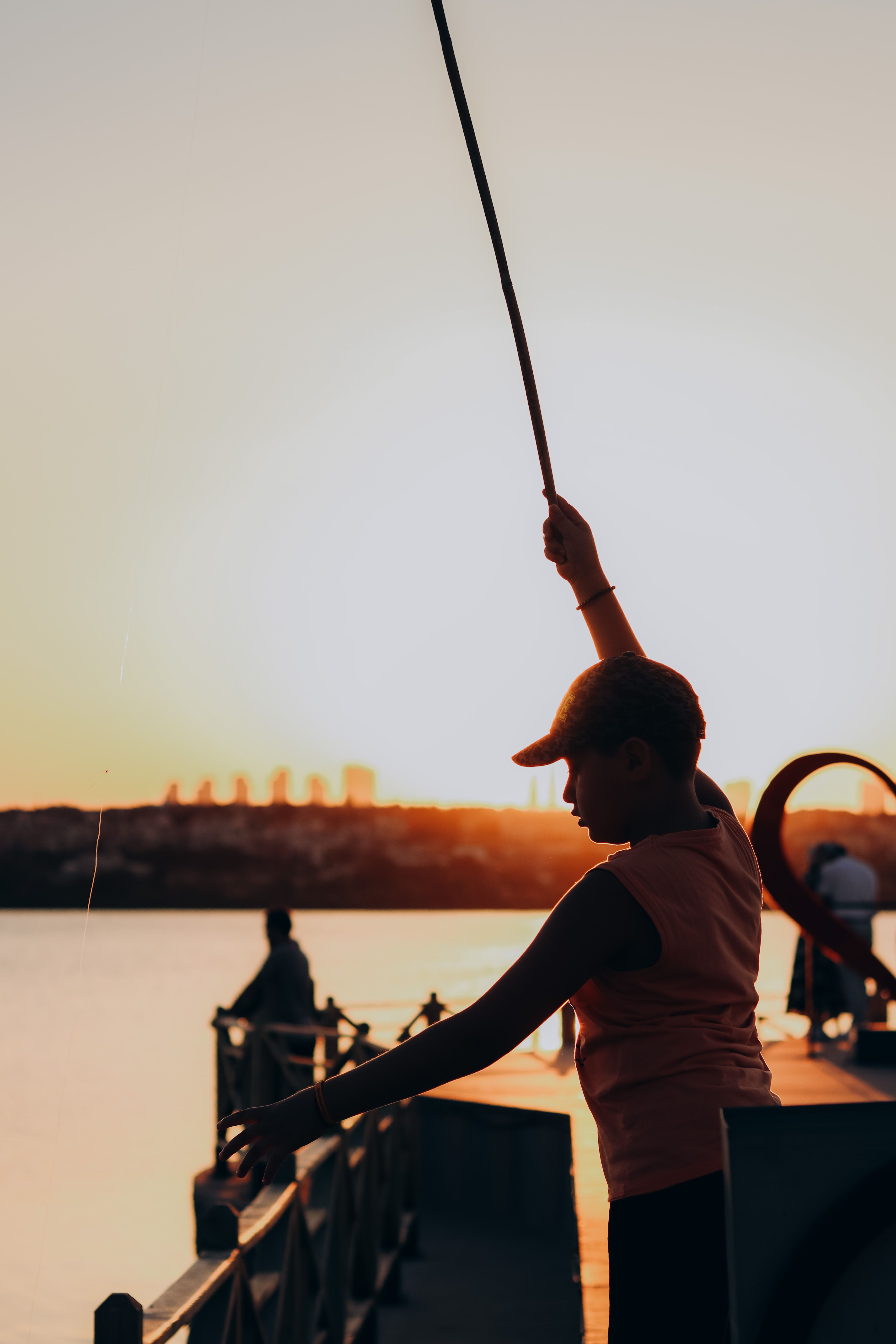 Person Standing with Arm Raised on Sea Shore at Sunset · Free Stock Photo