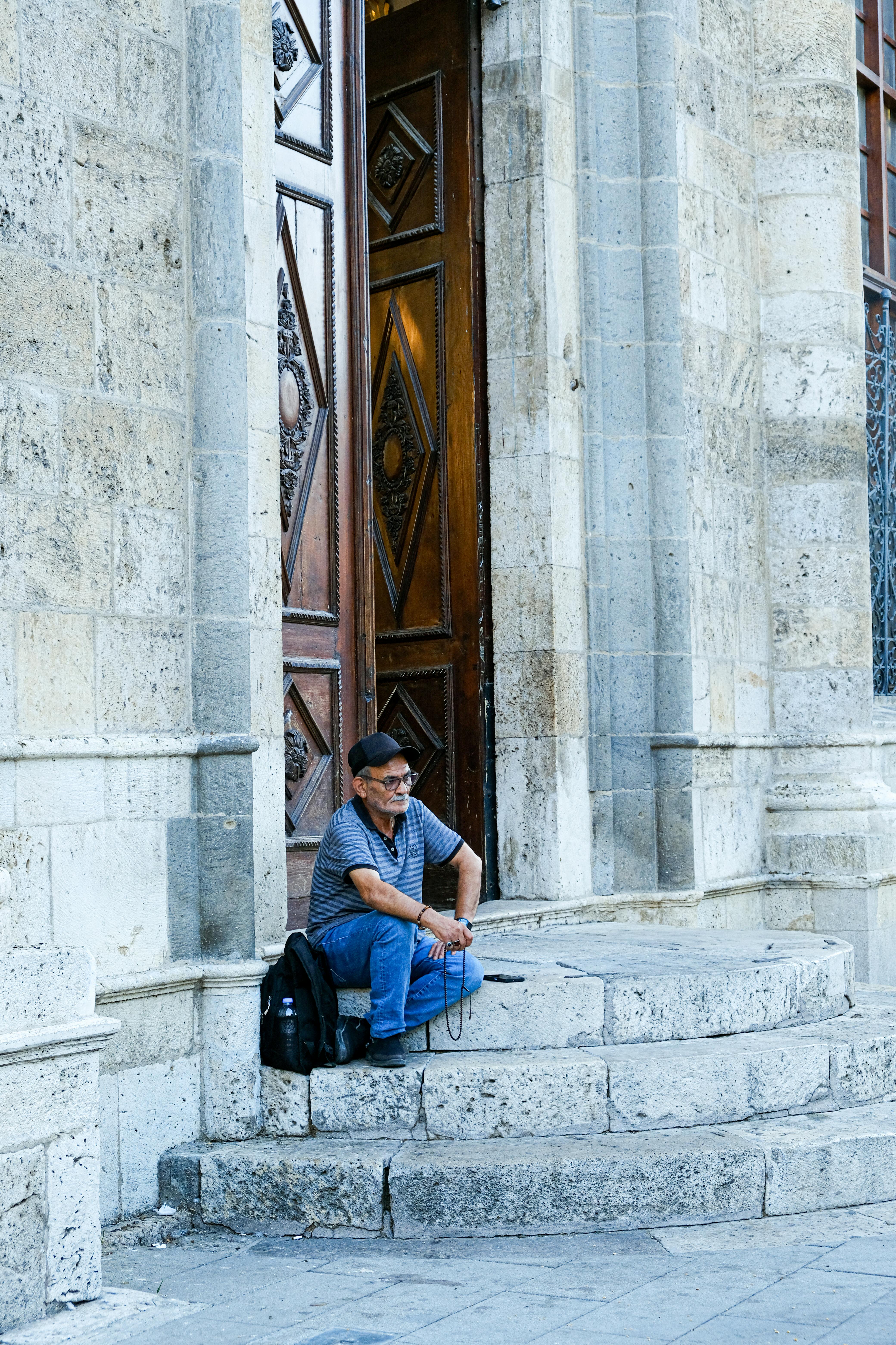 Man Sitting on Steps by Entrance · Free Stock Photo