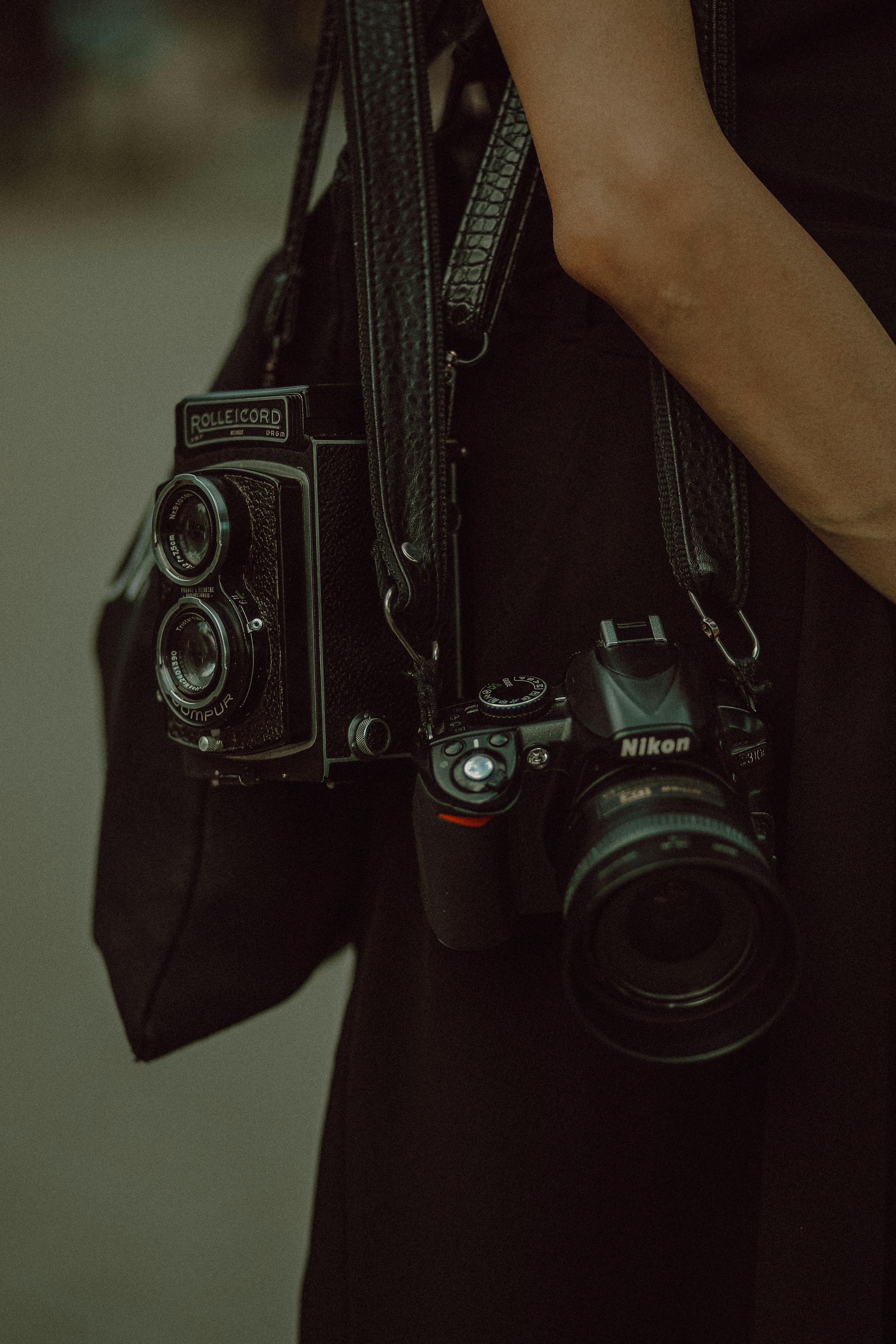 Cameras on Leather Straps Hanging from Persons Shoulder · Free Stock Photo