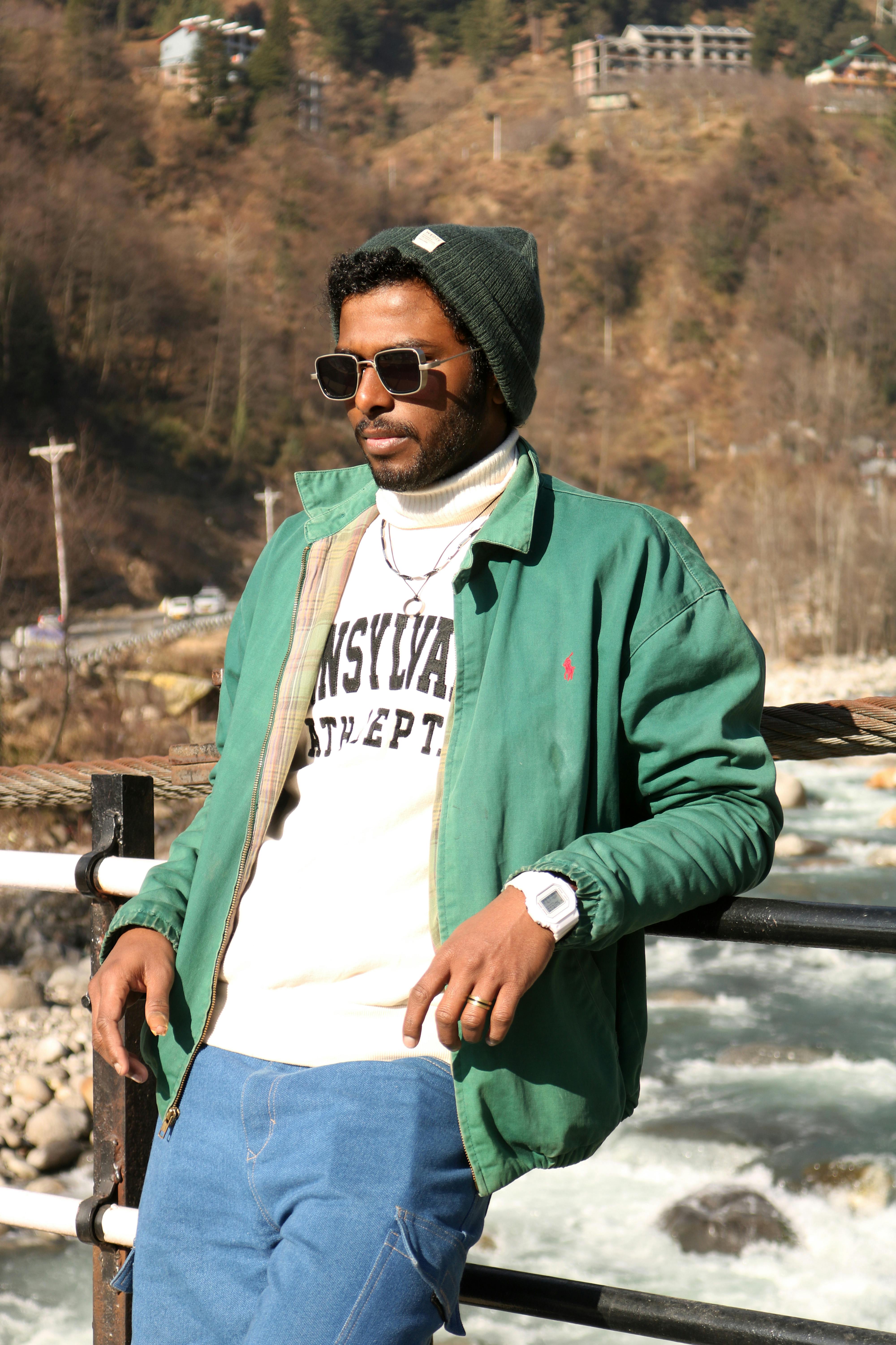 Man Wearing a Green Jacket Leaning against a Balustrade by a River ...