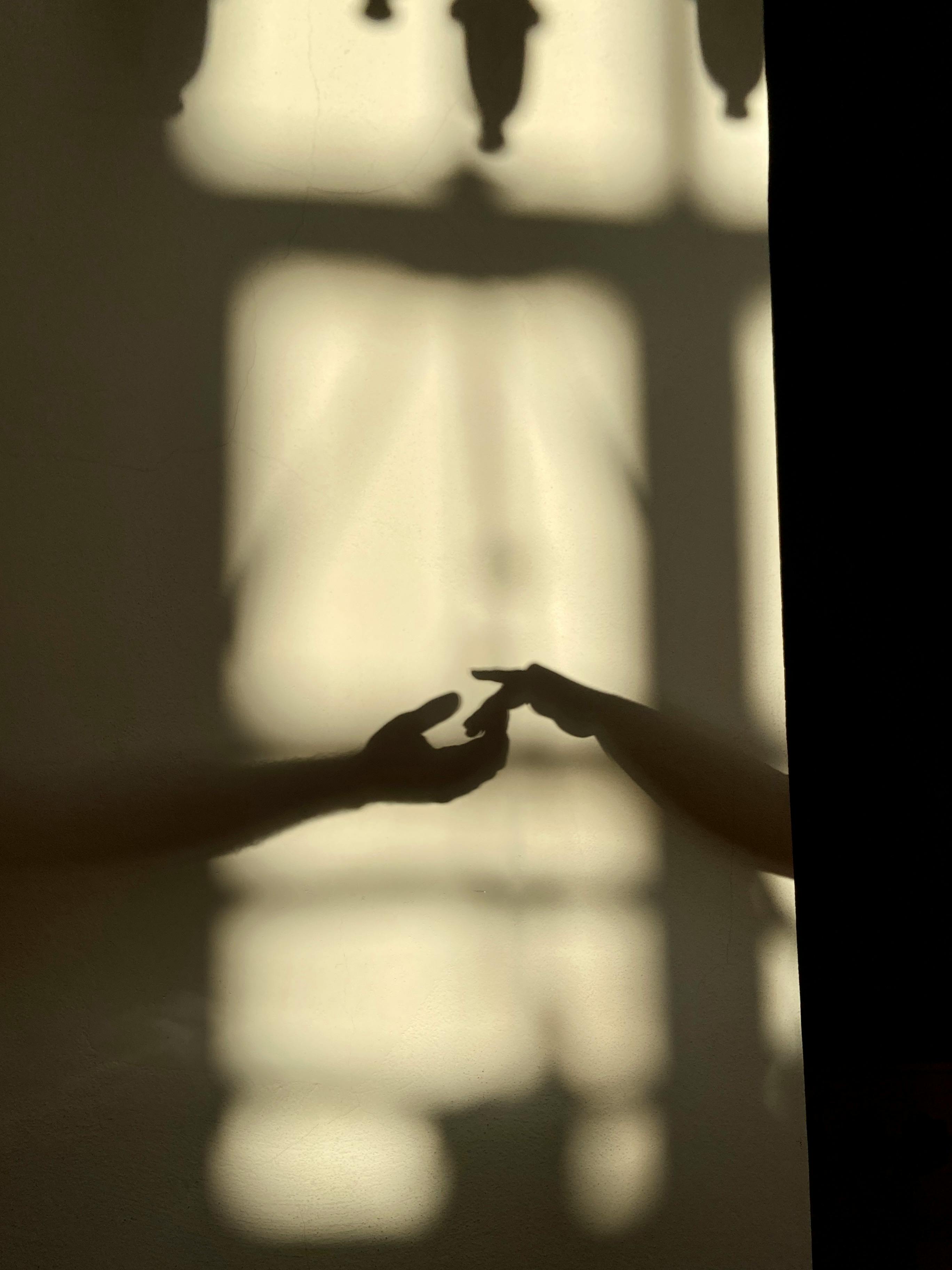 Couple Touching Hands in front of Shadow Cast on Wall · Free Stock Photo