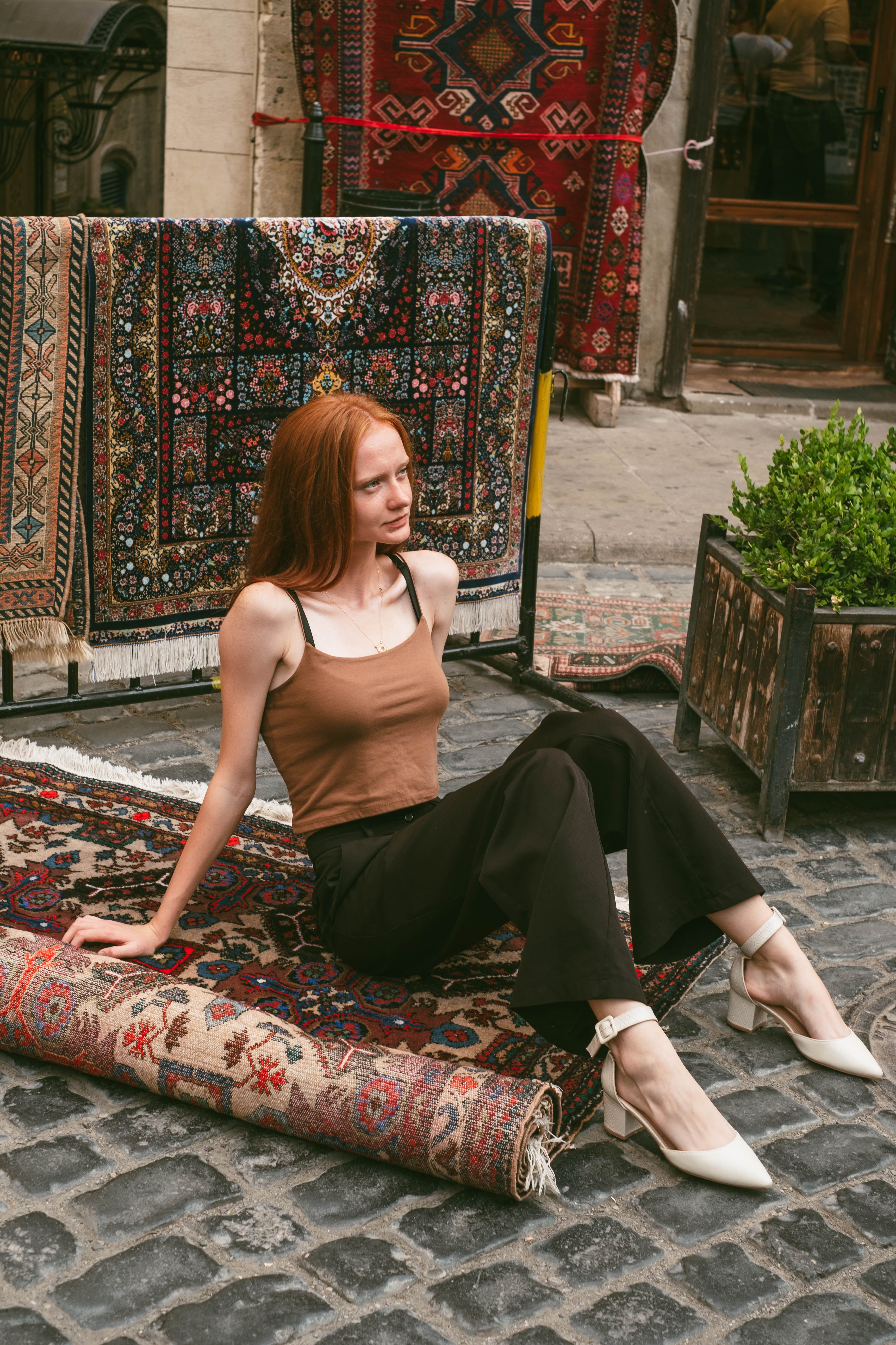 Woman Sitting on Carpet on Paving Street · Free Stock Photo