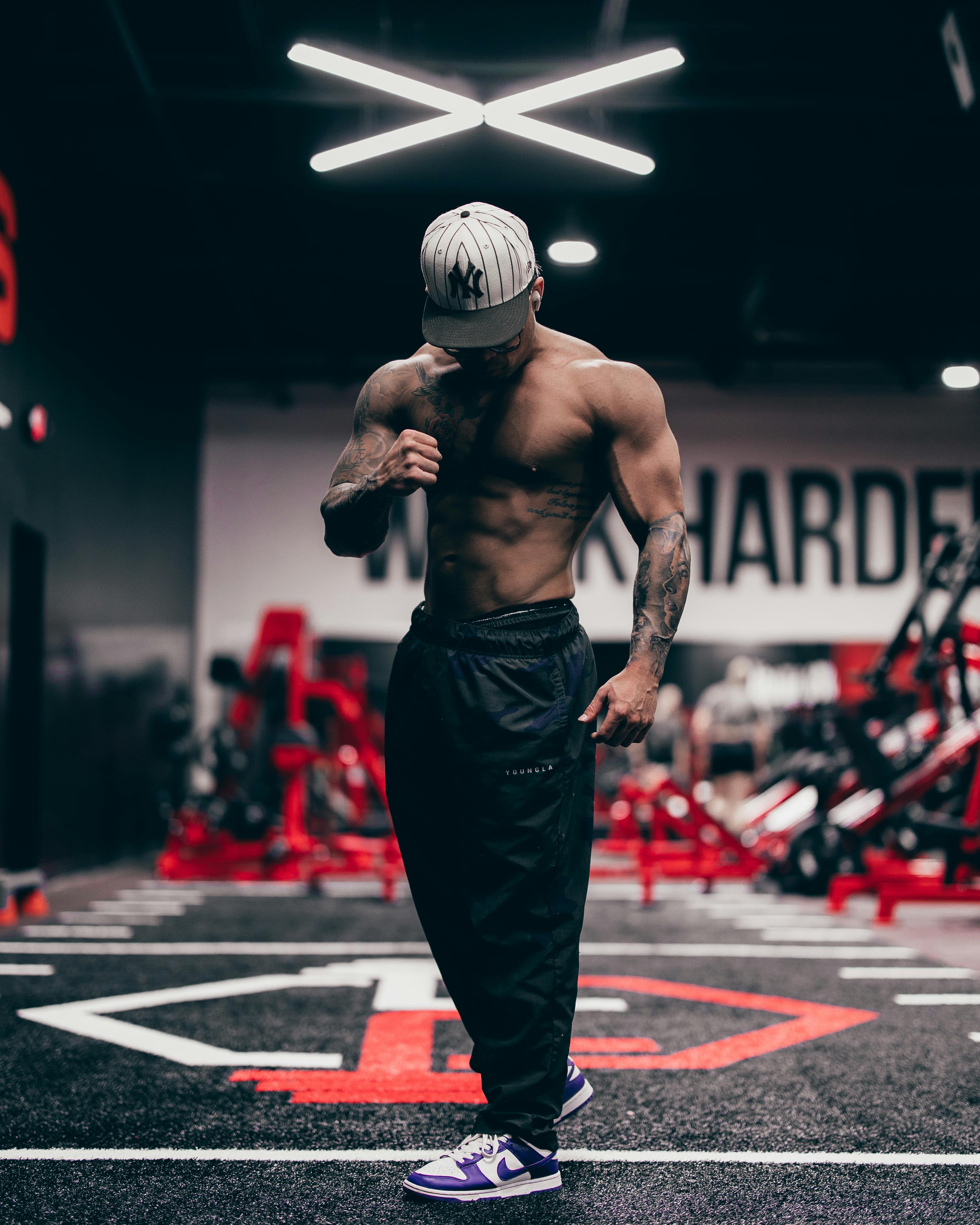 Tattooed Muscular Man Posing in the Gym · Free Stock Photo
