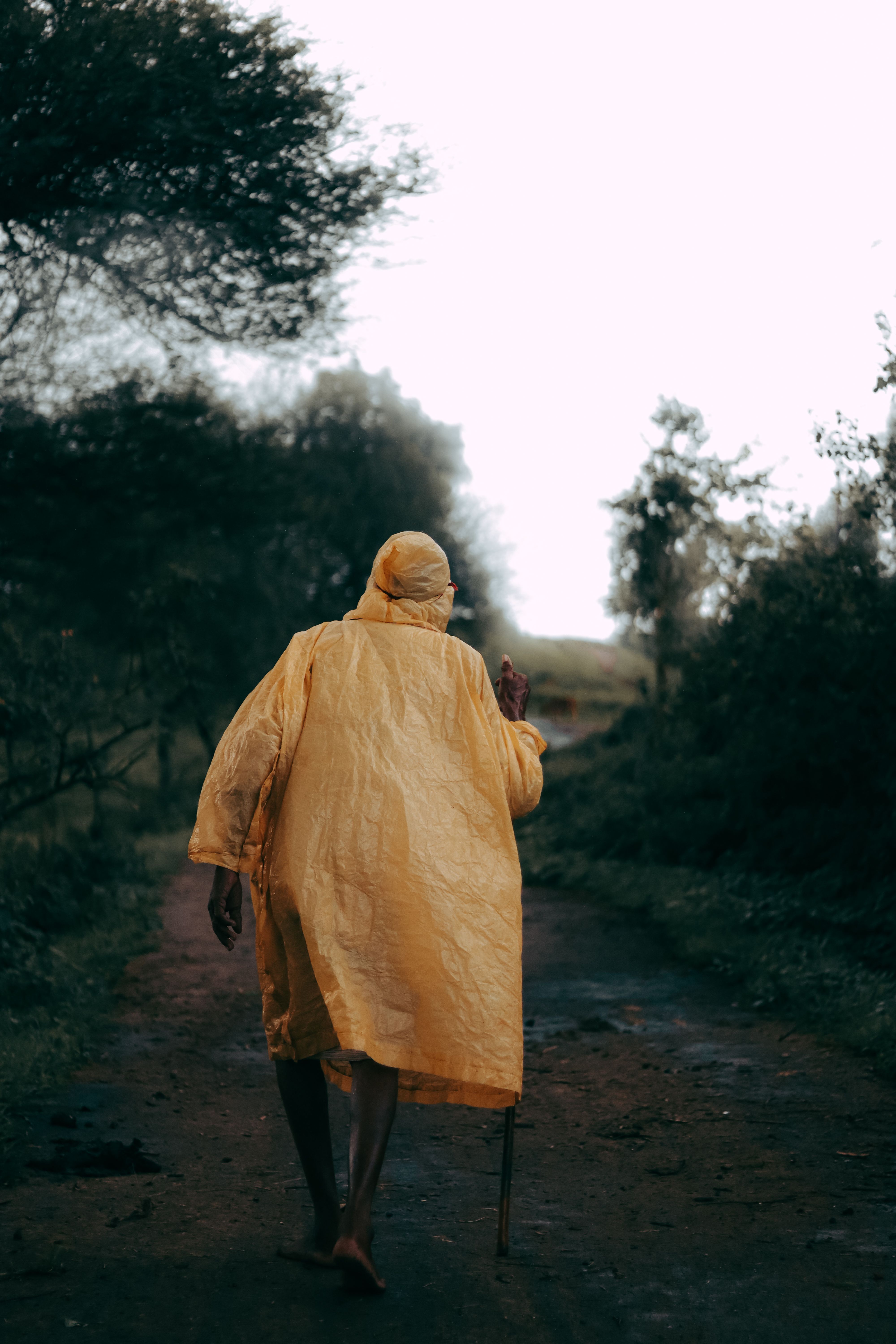 Barefoot Man in Raincoat Walking with Stick · Free Stock Photo