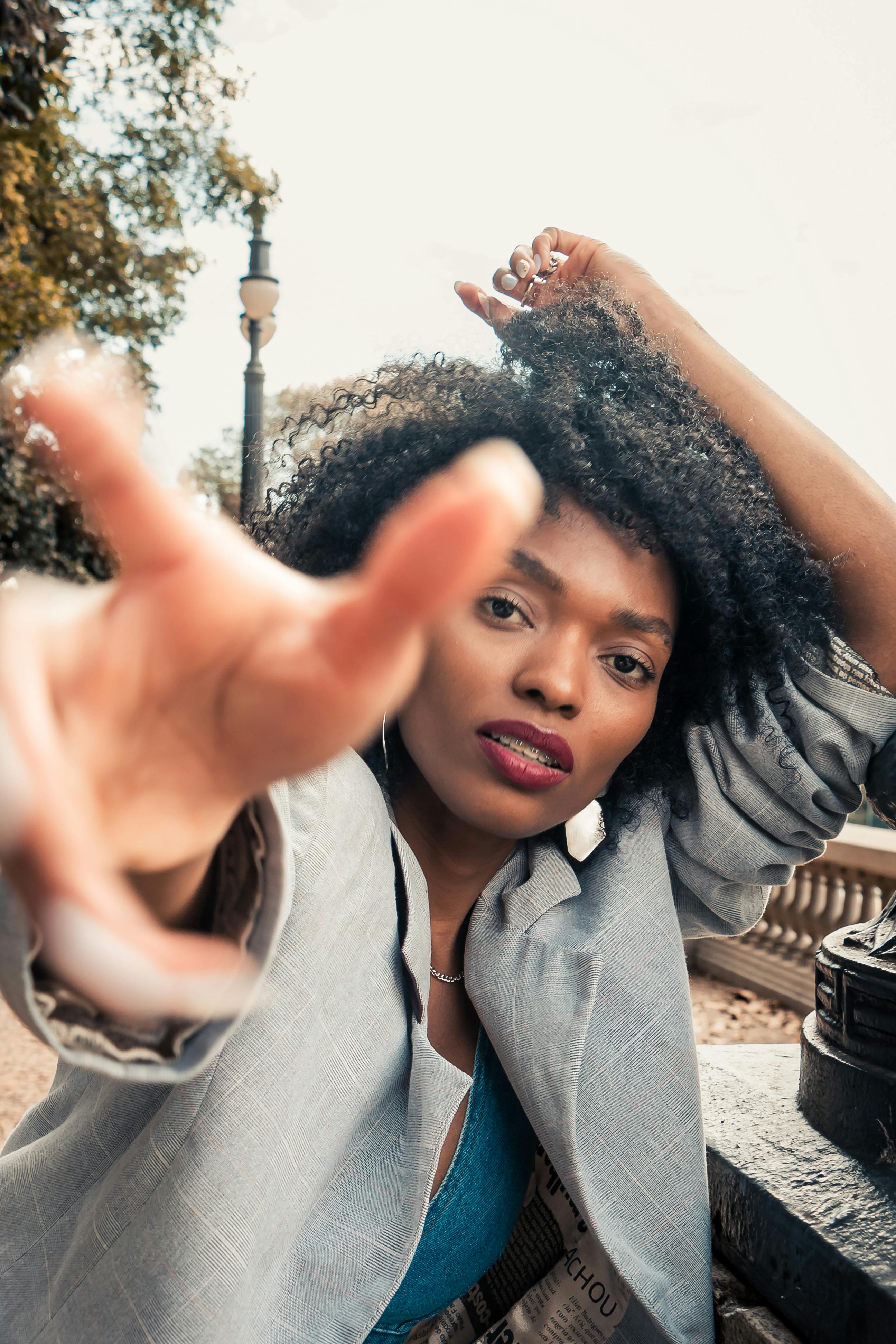 Young Fashionable Woman Posing Outside and Reaching Her Hand Toward the ...