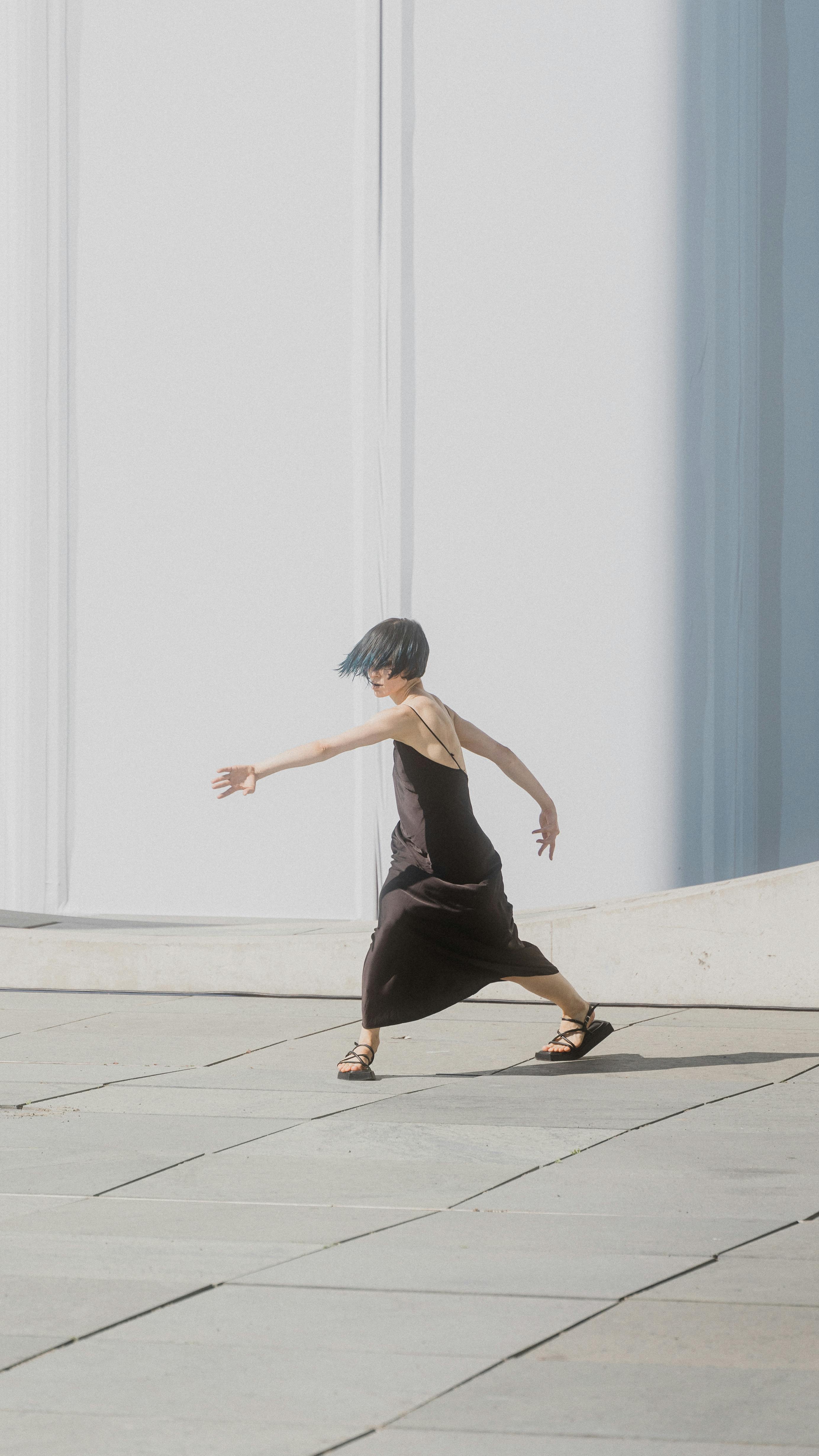Woman in Black Dress Walking on Pavement · Free Stock Photo