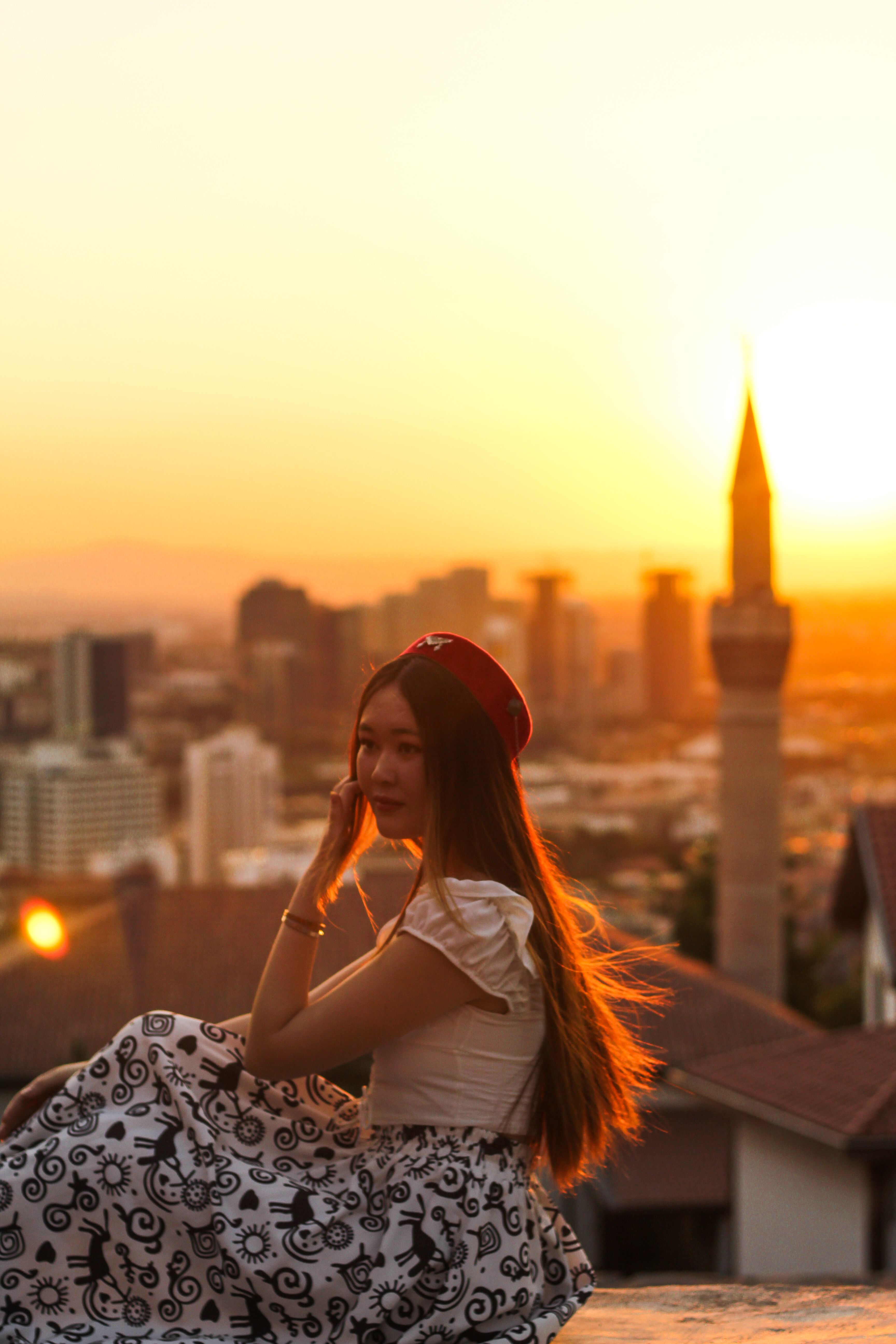 Woman Sitting and Posing with Minaret behind at Sunset · Free Stock Photo