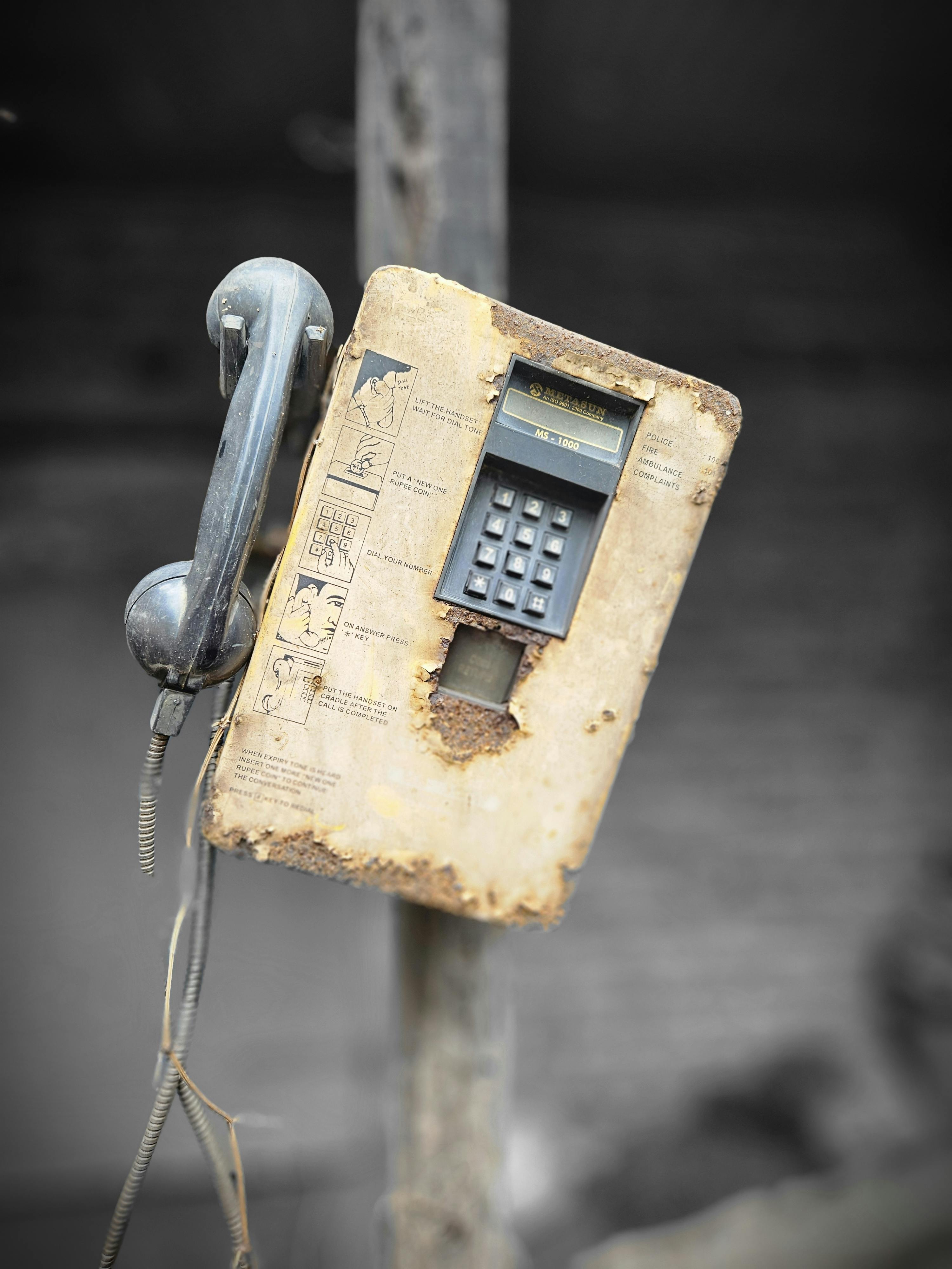 Old Vandalized Payphone Barely Hanging From the Post · Free Stock Photo